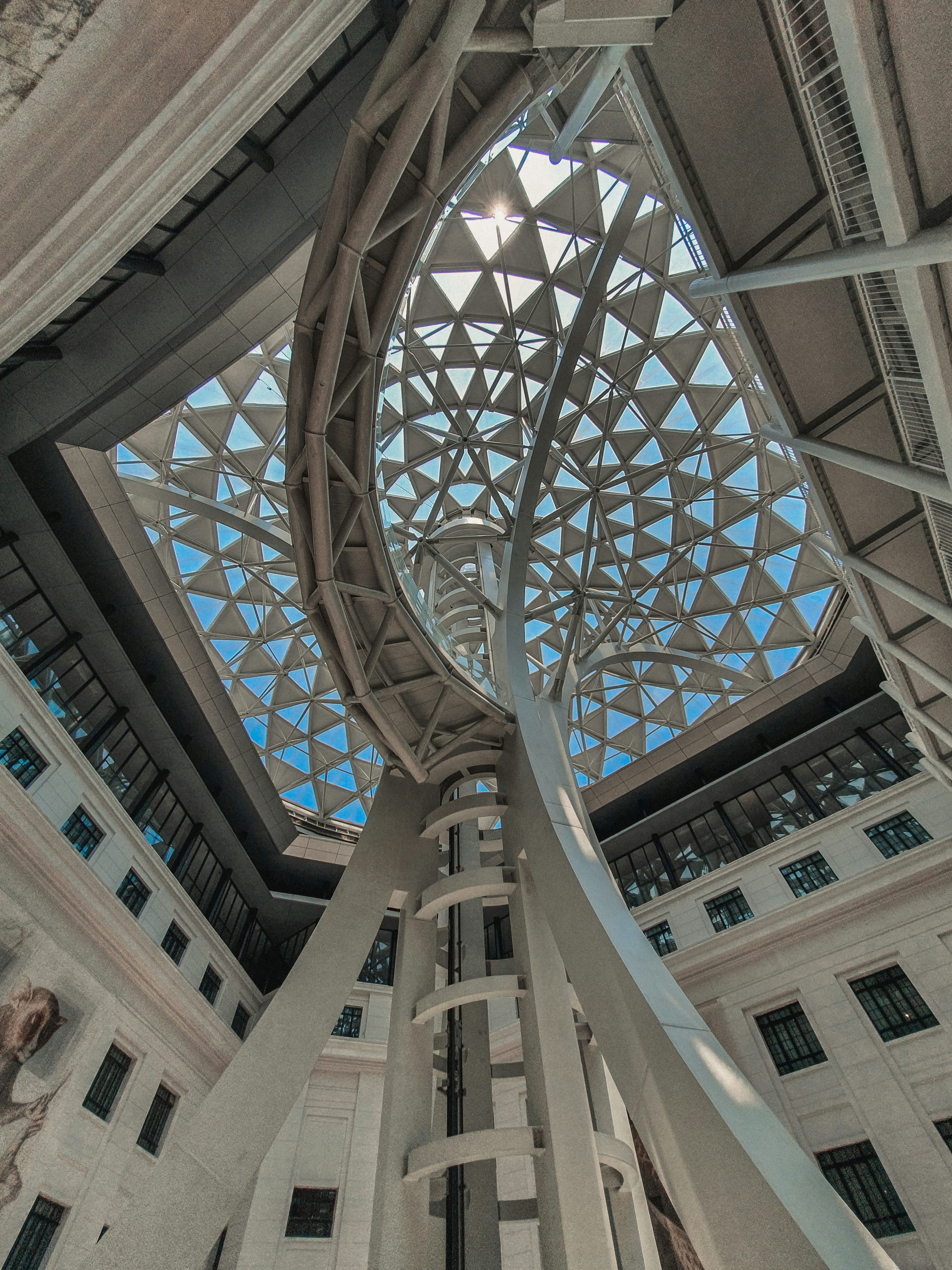Geometric Cathedral: A Sunlit Atrium Framed by Spiral Support and Glass Lattice