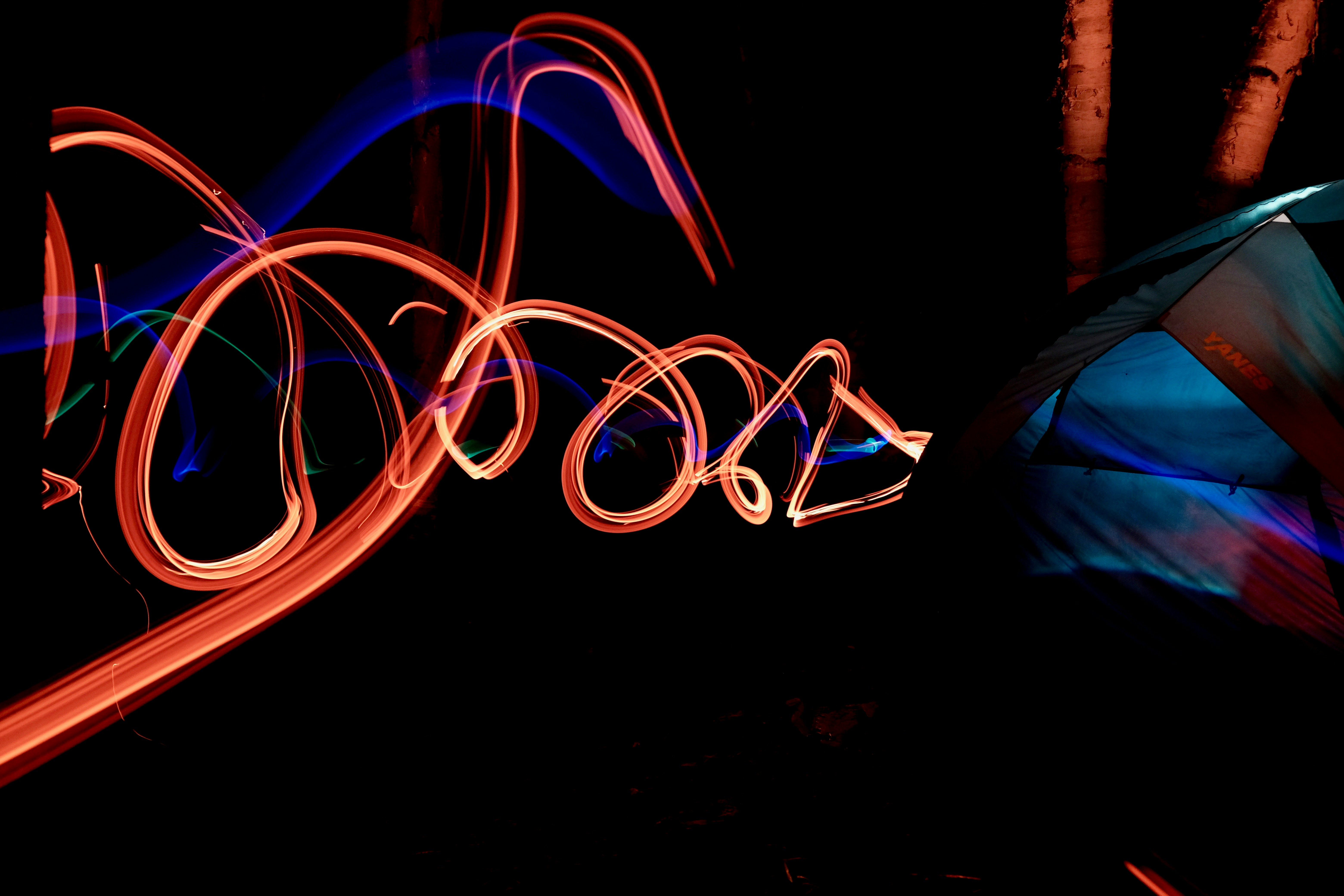 Lantern Trails: Neon Streaks Over a Tent at Night