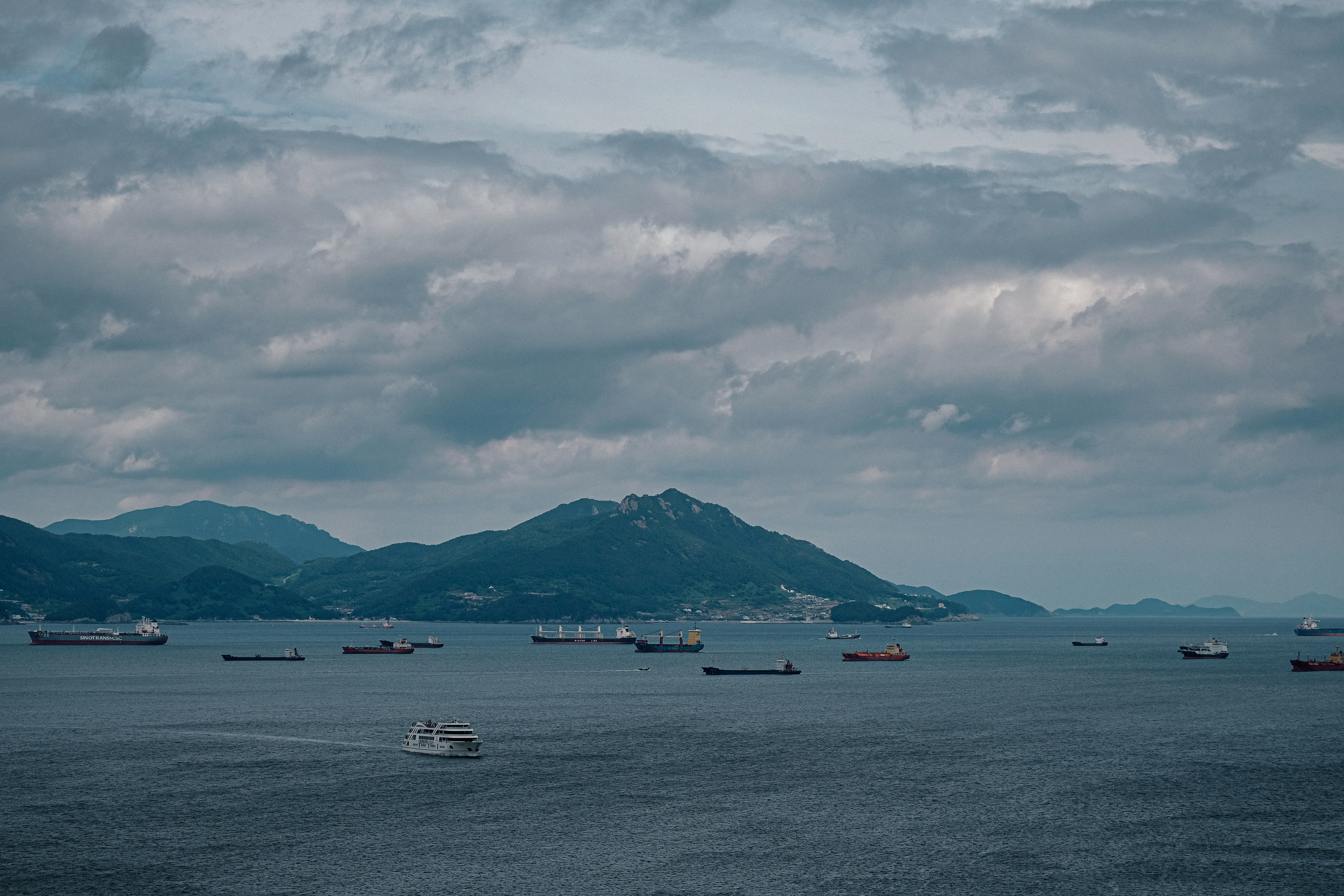 sea beside mountain range under cloudy sky photo – Free Grey Image on ...