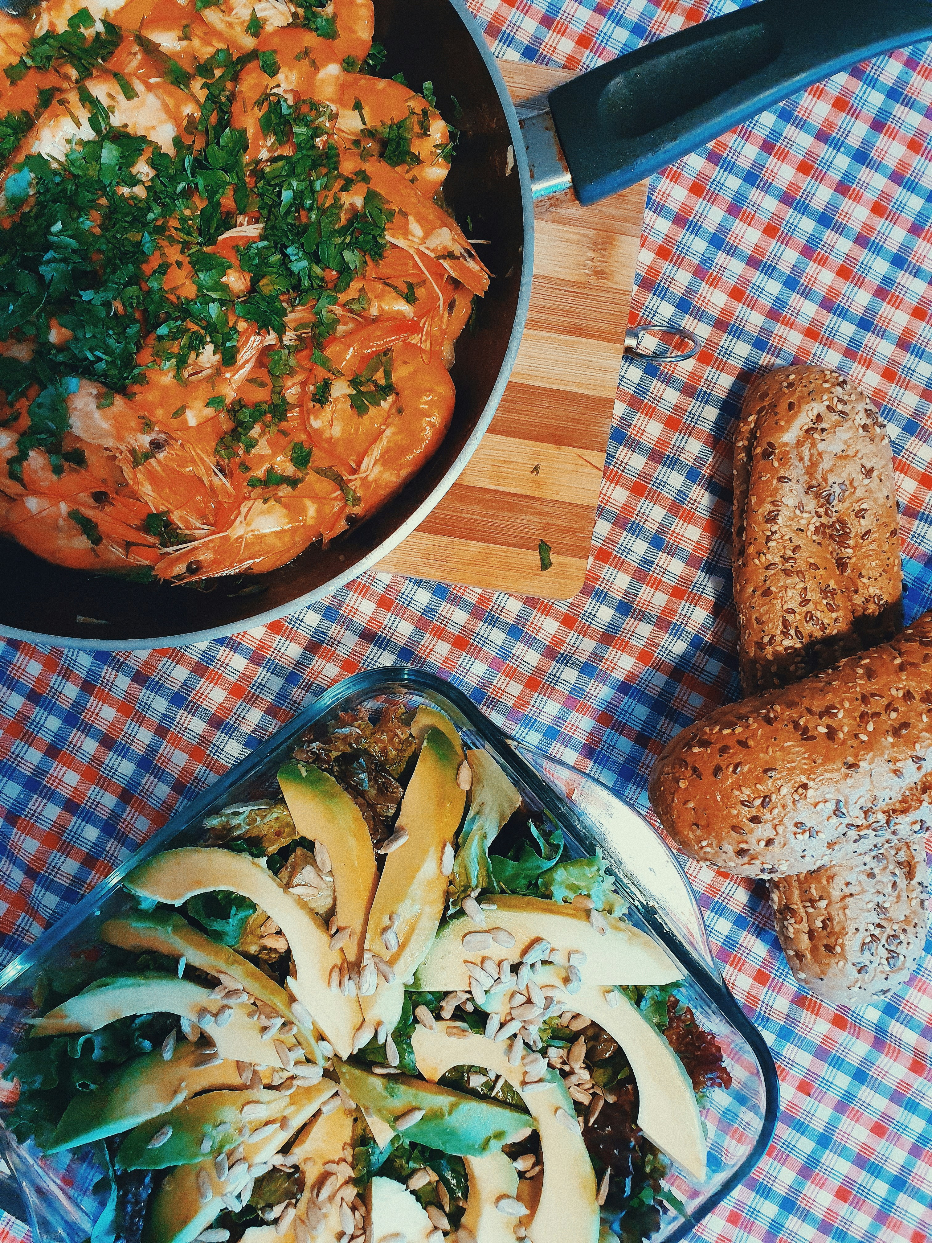 Herbed Shrimp Skillet on a Plaid Tabletop, Framed by Avocado Salad and Multigrain Bread