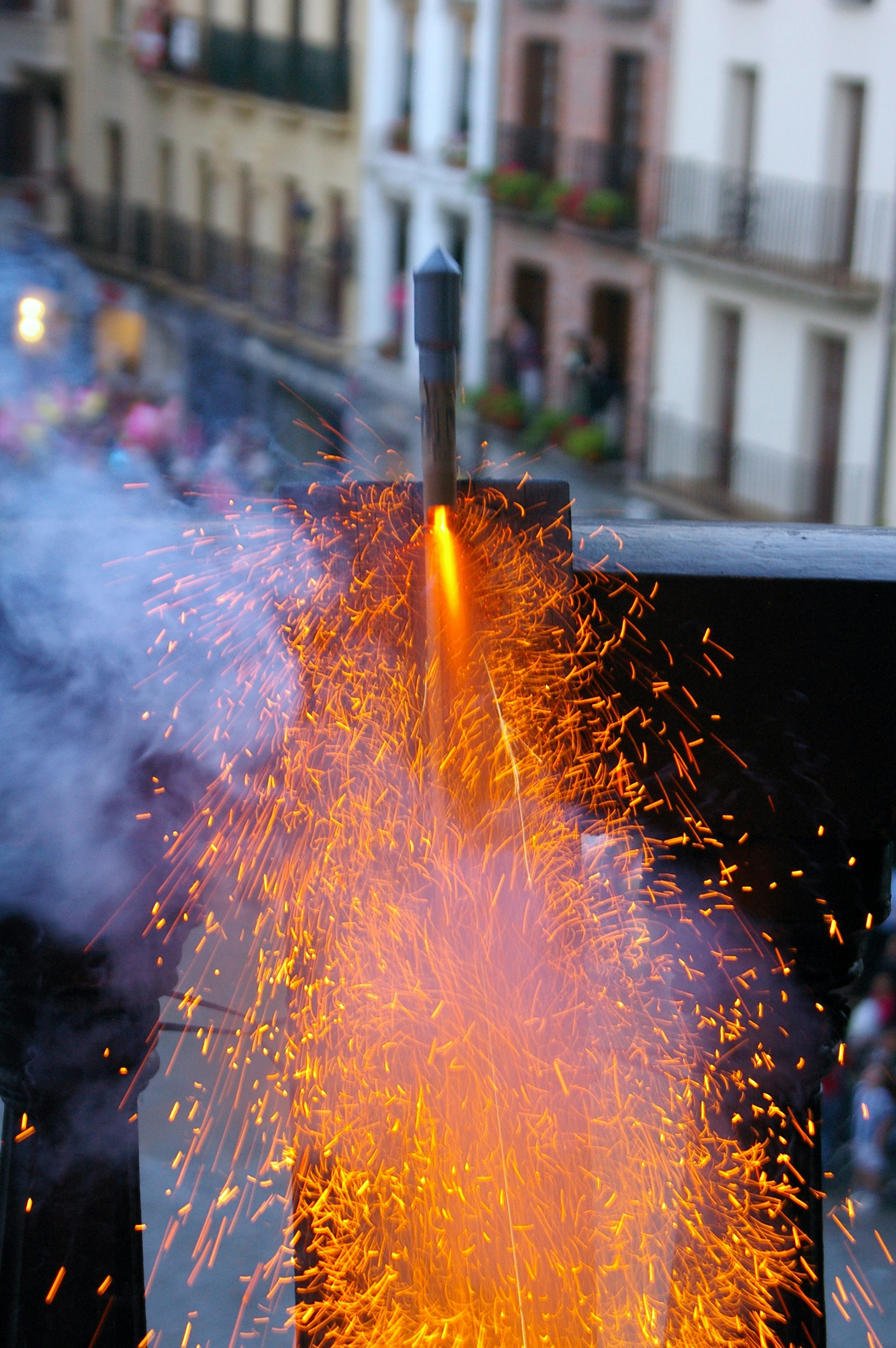Firework igniting with vibrant sparks against a blurred urban backdrop, capturing the essence of festivity.