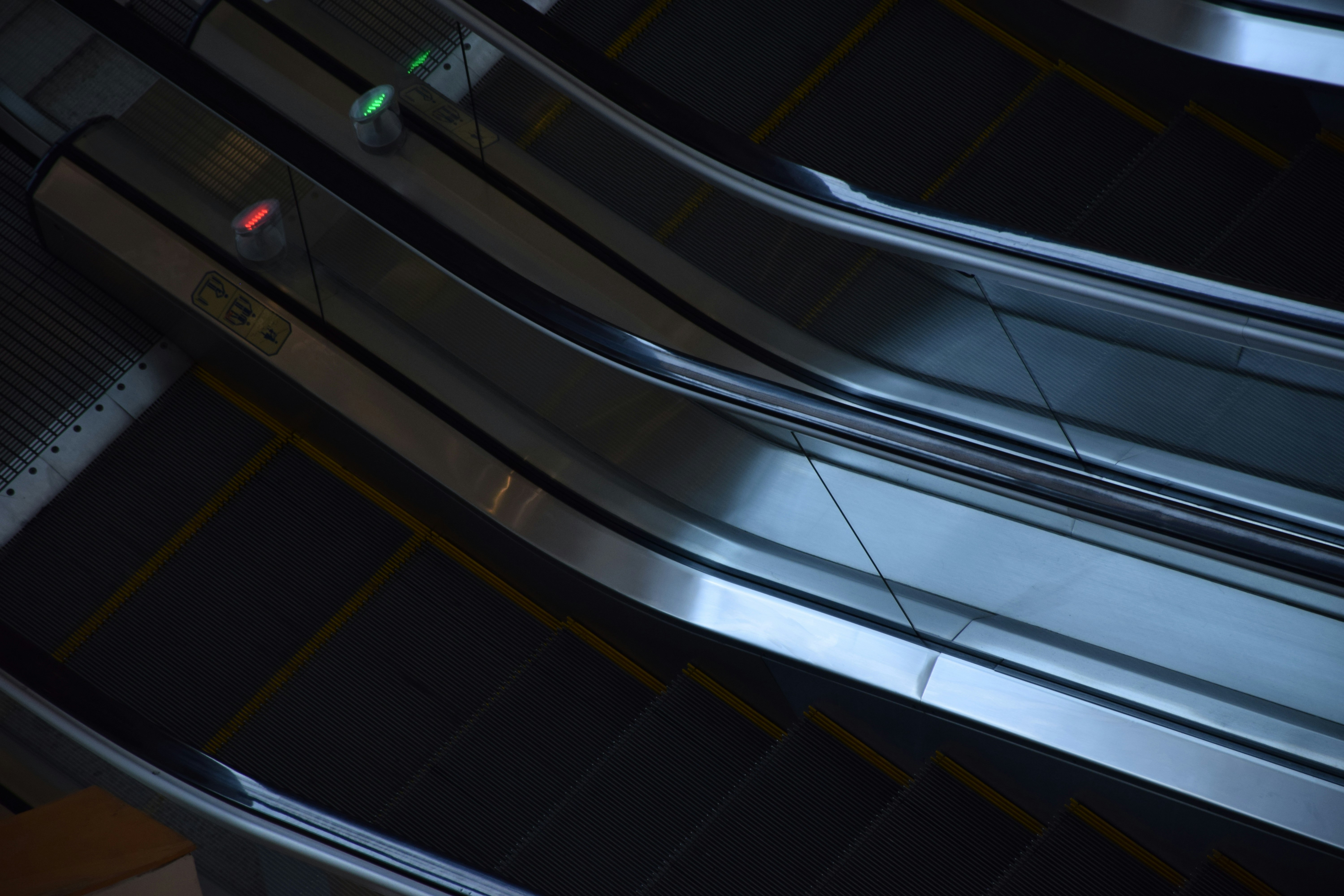 Curved escalator surfaces highlighted by contrasting red and green lights, showcasing a modern architectural design.