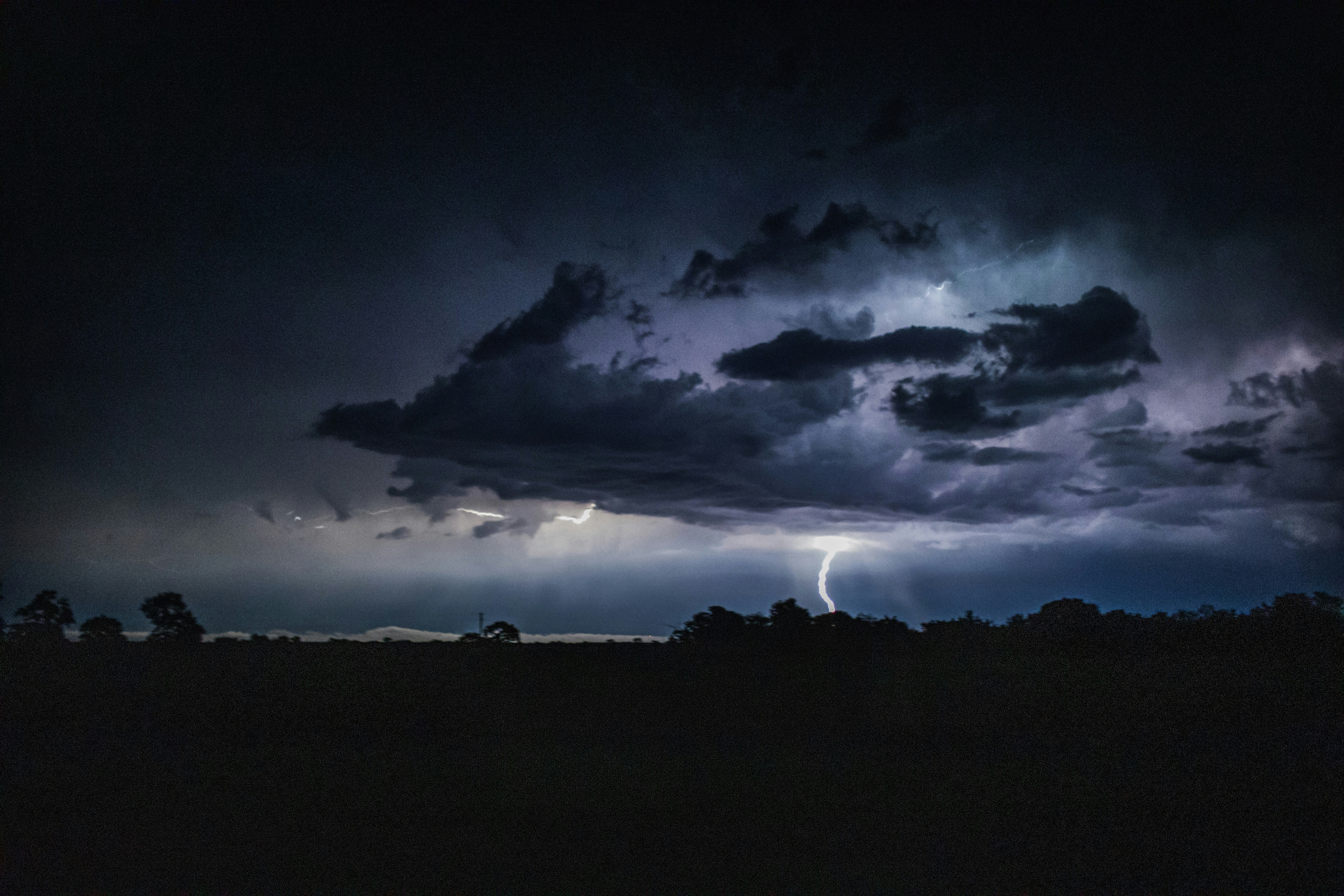 Dramatic lightning illuminating a dark stormy sky, with ominous clouds swirling above the horizon.
