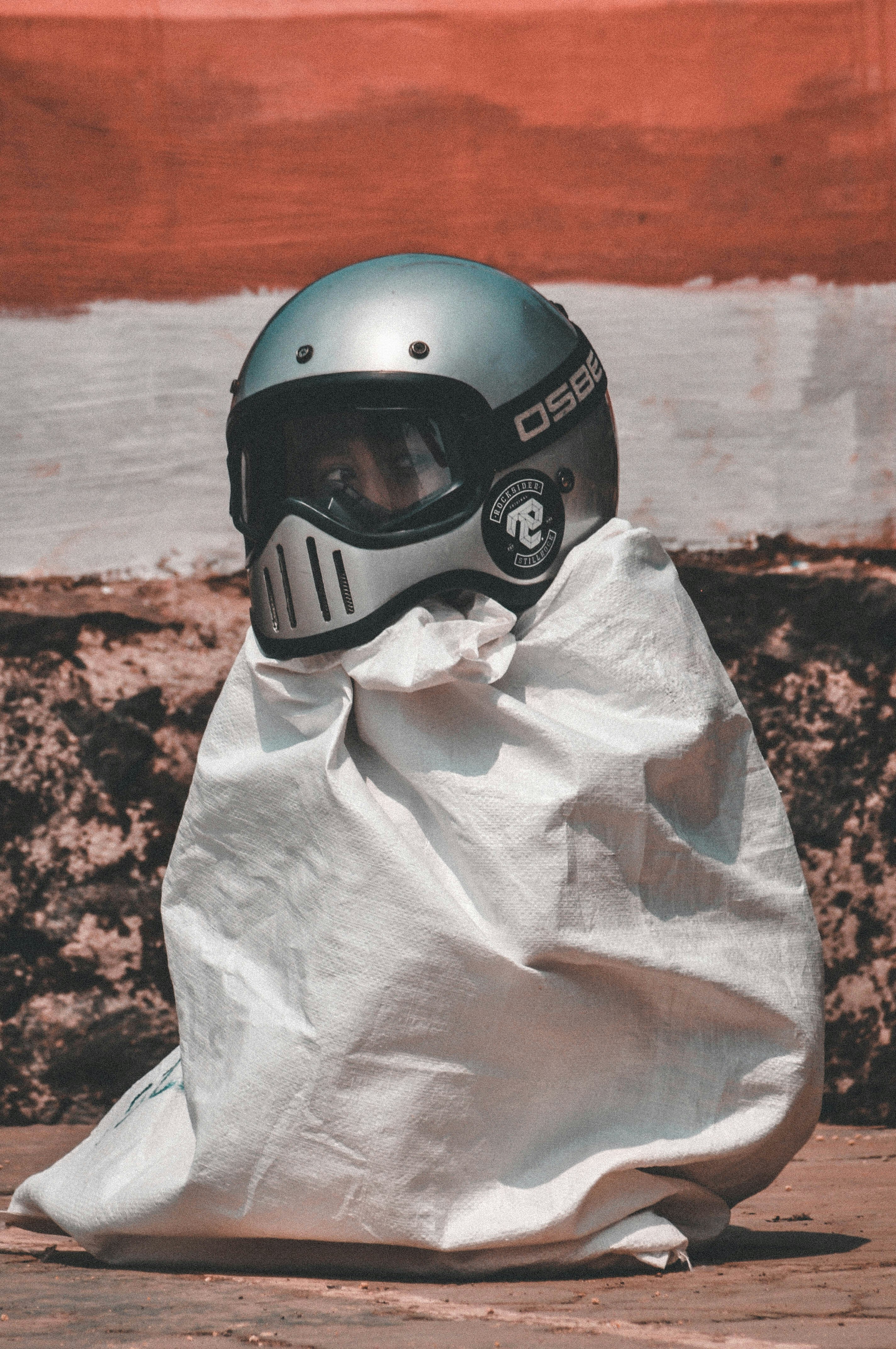 Masked Figure Emerges from a White Sack in an Outdoor Scene