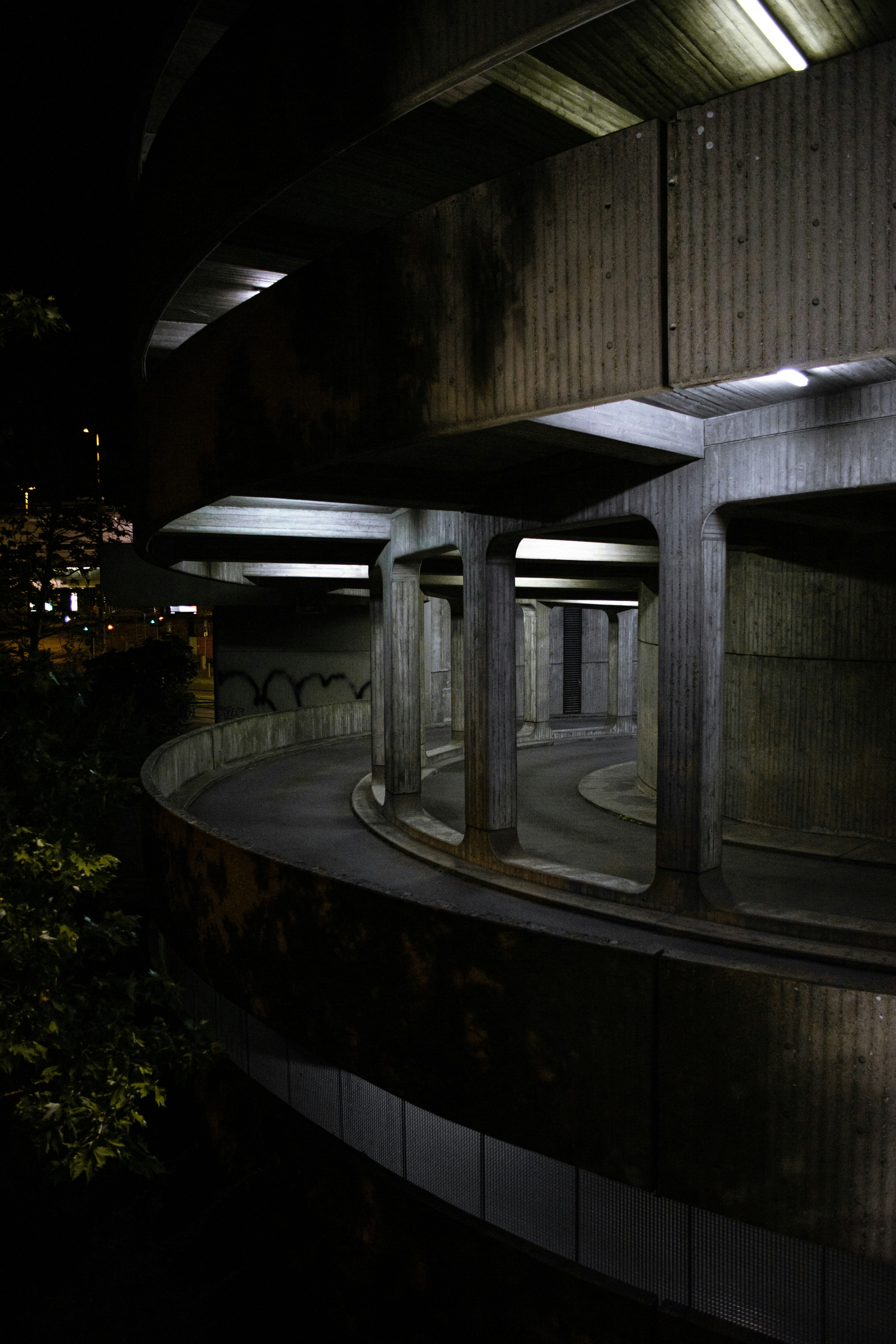 An intricate concrete structure with illuminated columns and a winding path, showcasing modern architectural design at night.
