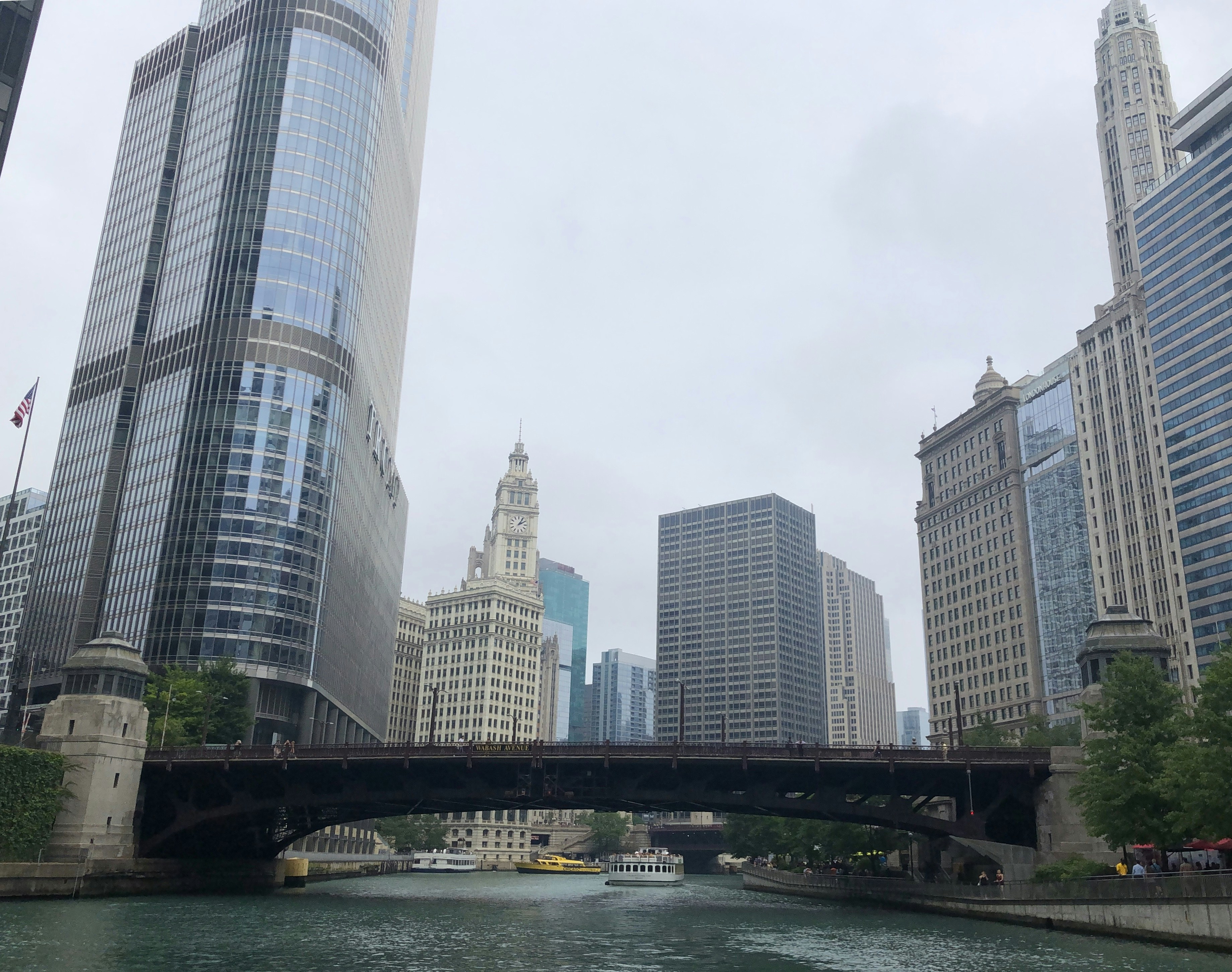 A view of the Chicago River flanked by towering skyscrapers and a historic bridge, showcasing the blend of modern architecture and urban life.