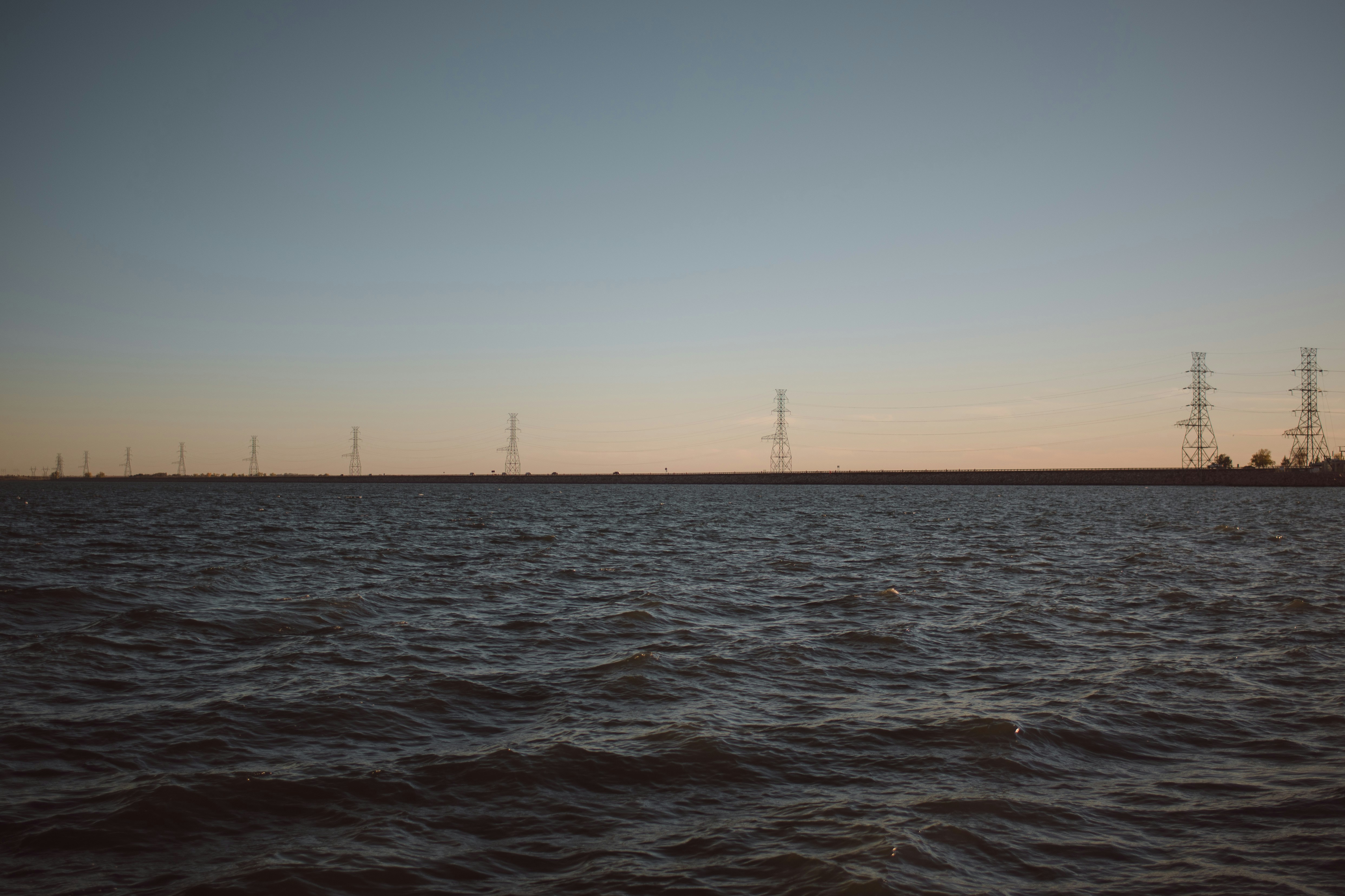 Dusk Across the Quiet Channel: Silhouetted Transmission Towers on the Horizon