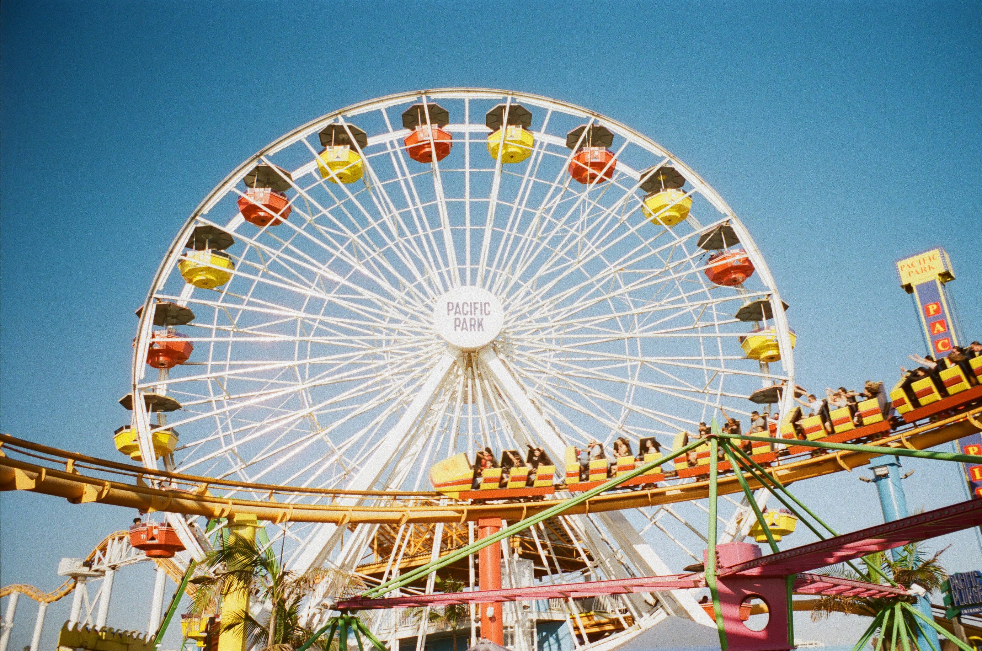 White fairy's wheel near roller coaster under blue sky during daytime ...
