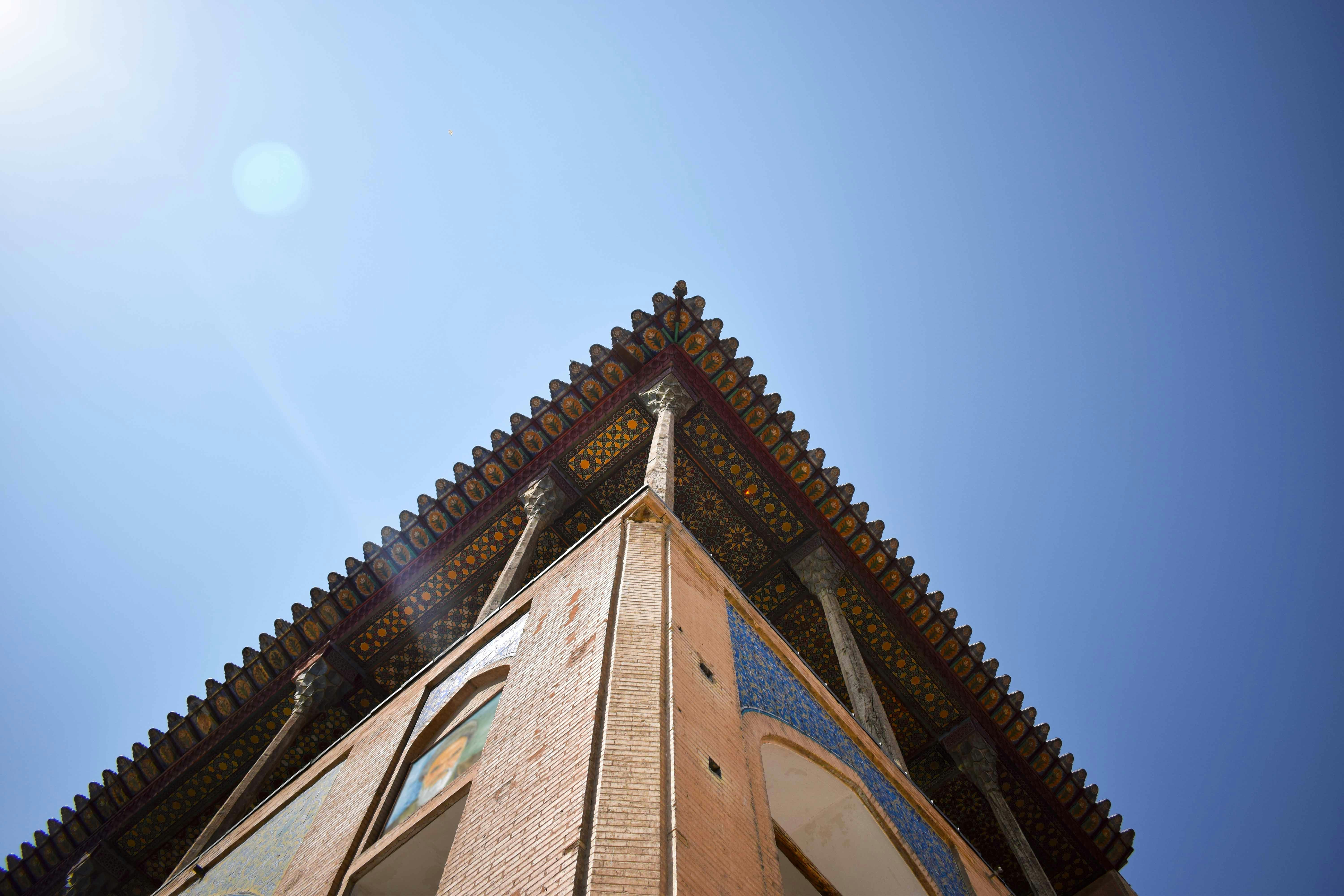 Corner view of a historic building with intricate wooden eaves against a clear blue sky.