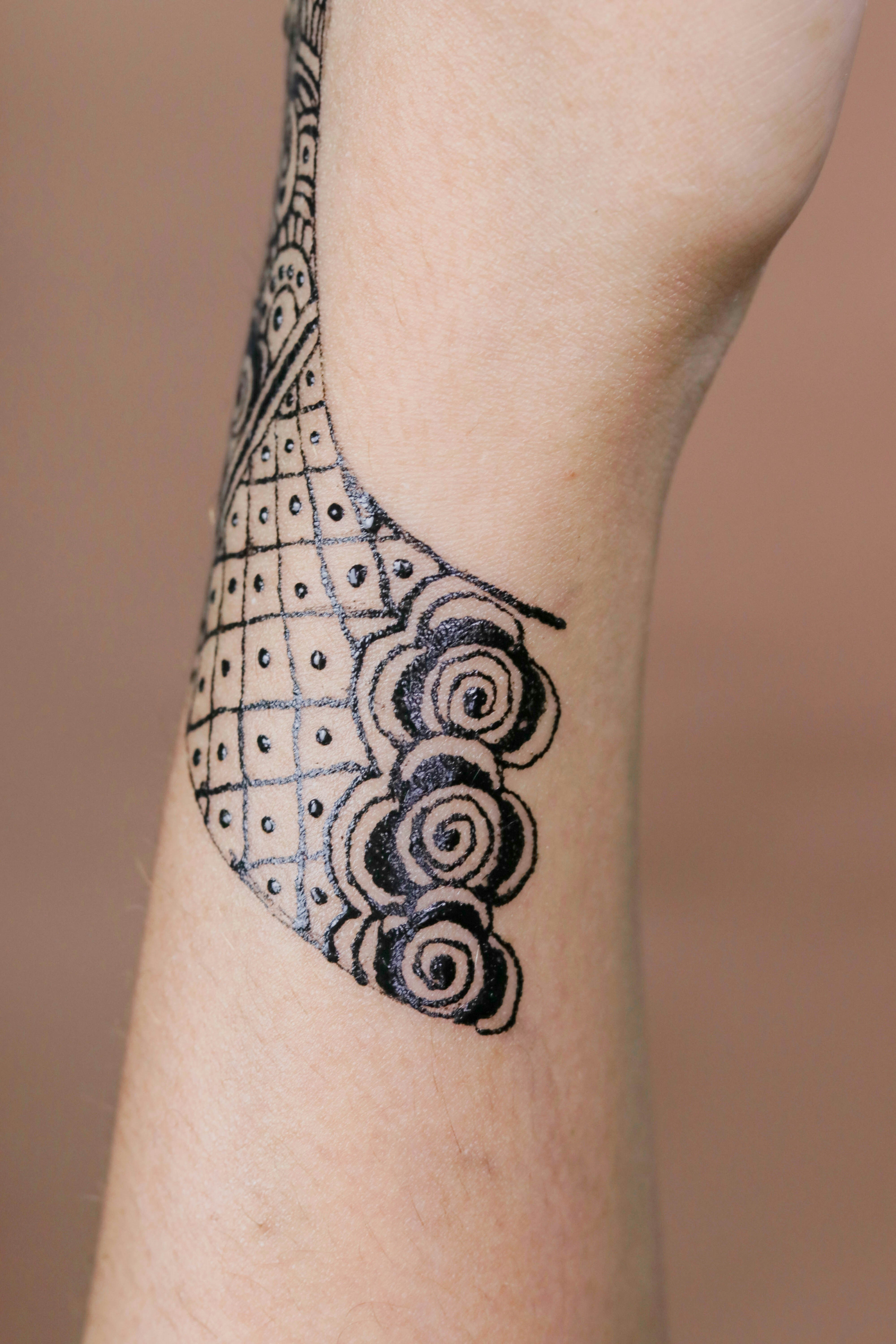 Geometric Lace on Skin: a close-up tattoo of mesh grid and curling spirals along the calf