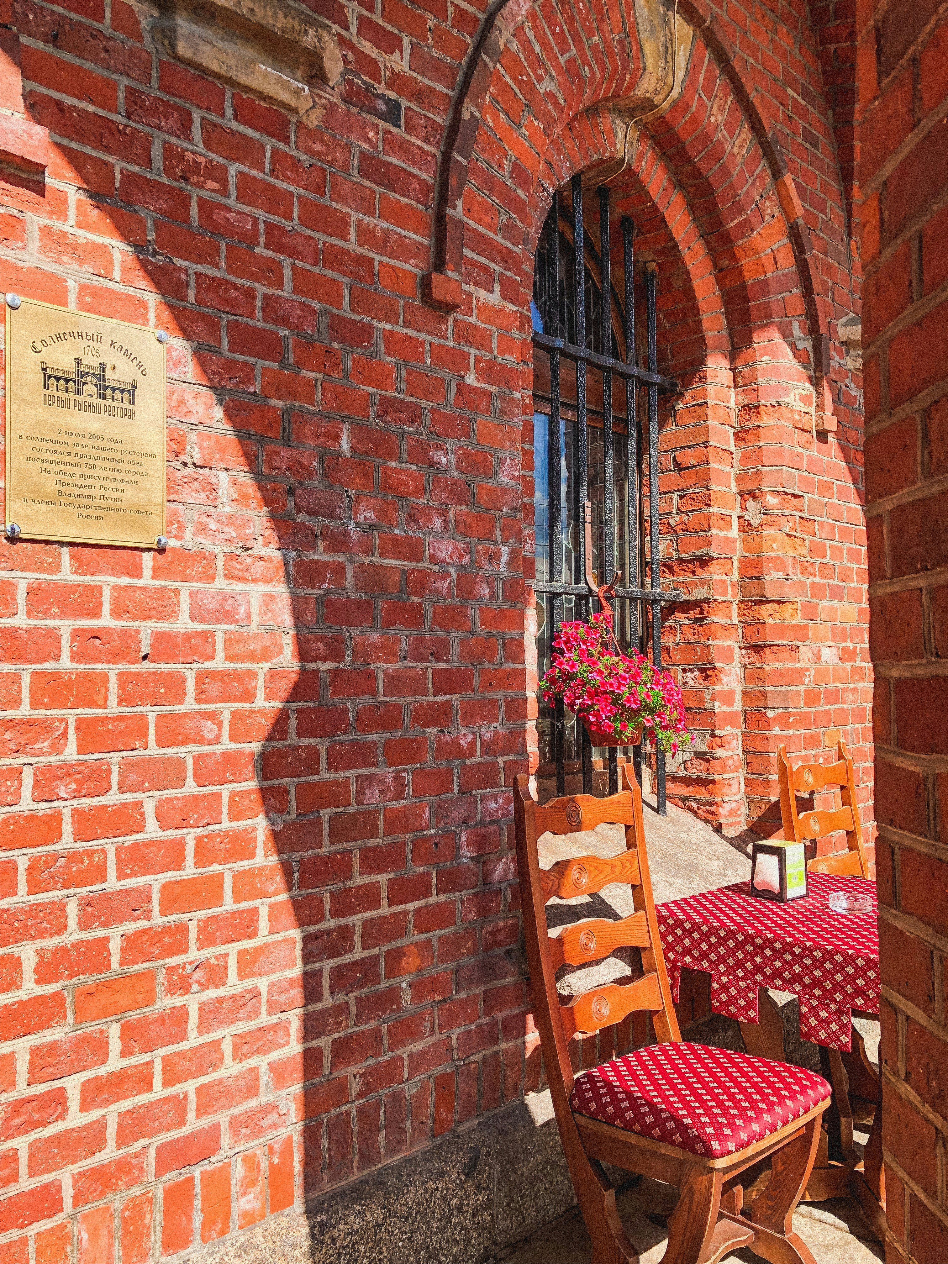 Sunlit Bricks and a Red-Checked Table: Courtyard Calm Under an Arch