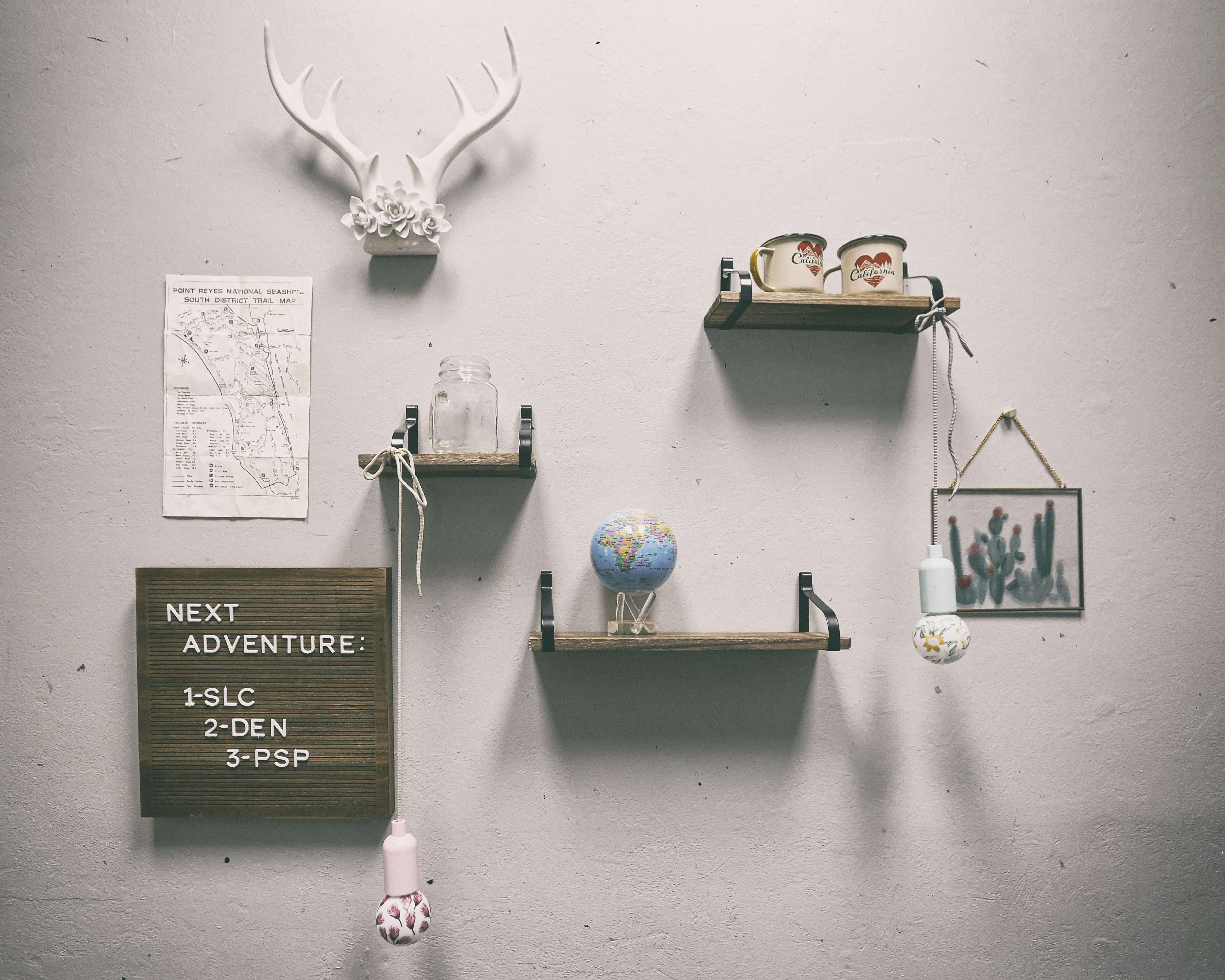 Minimalist wall display featuring floating shelves with eclectic decor, including antlers and framed art.