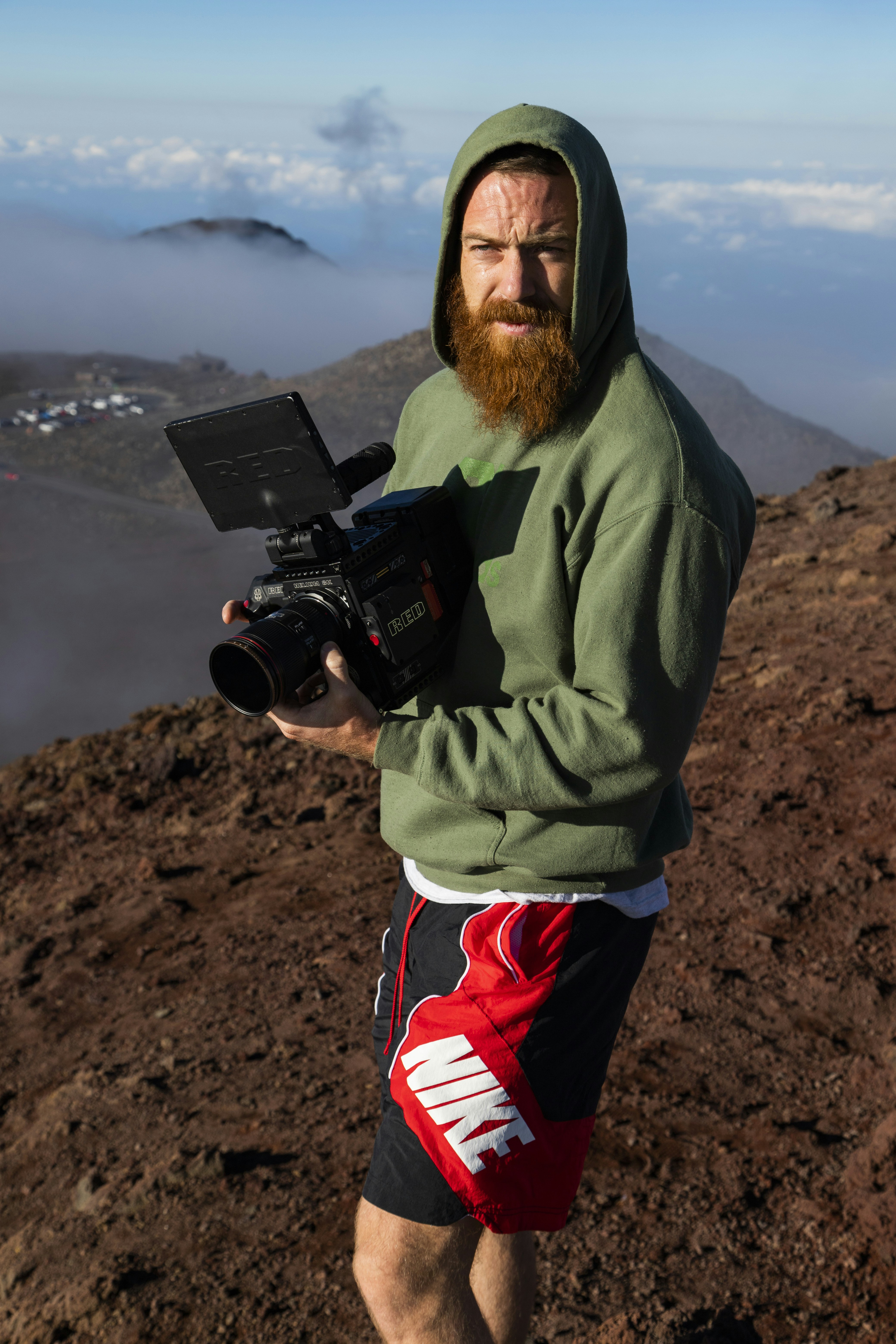 Bearded Cinematographer on a Lava-Dusted Summit with a Pro Rig