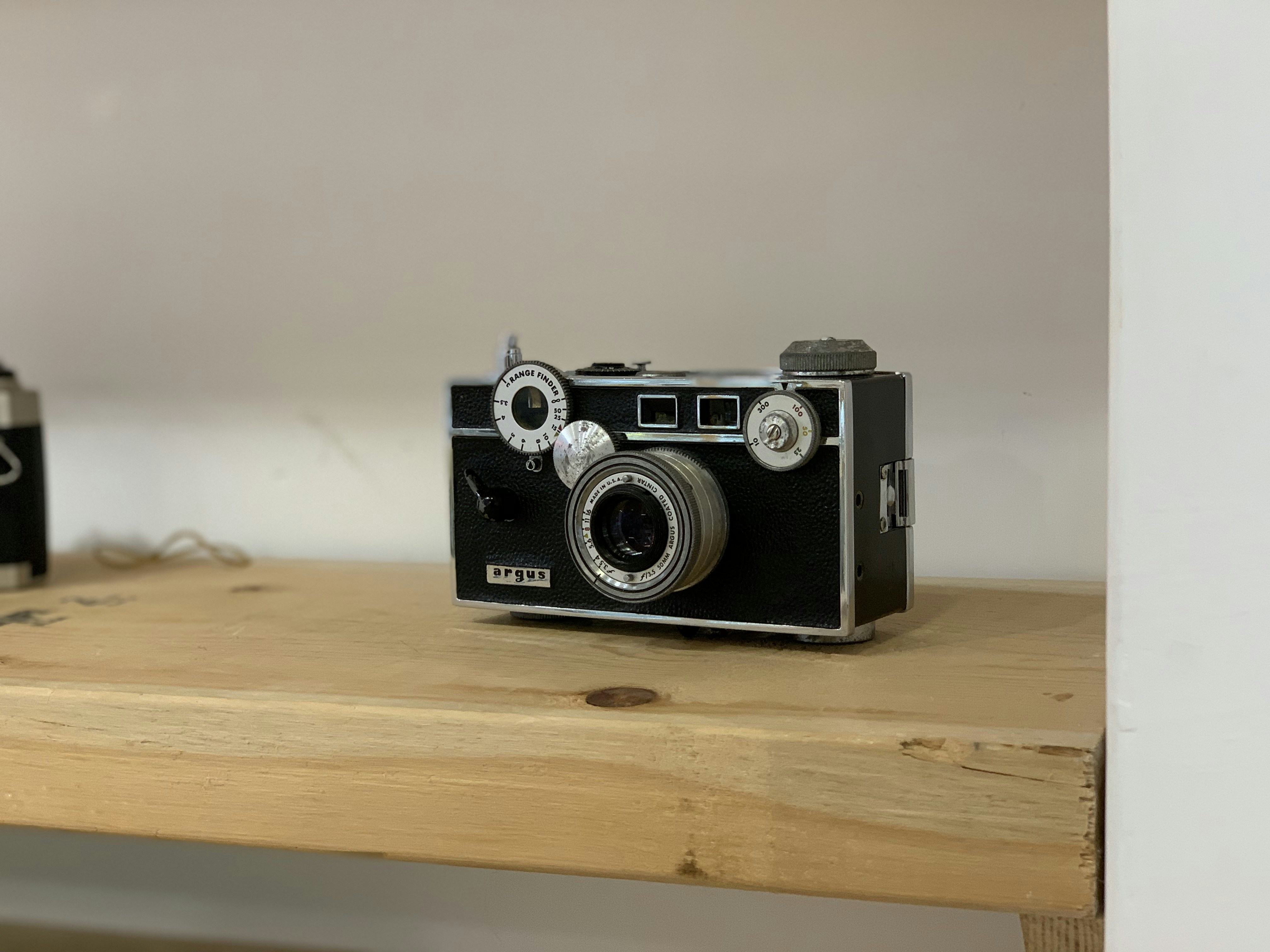 Ledge of memory: a vintage rangefinder rests on a plain wooden shelf