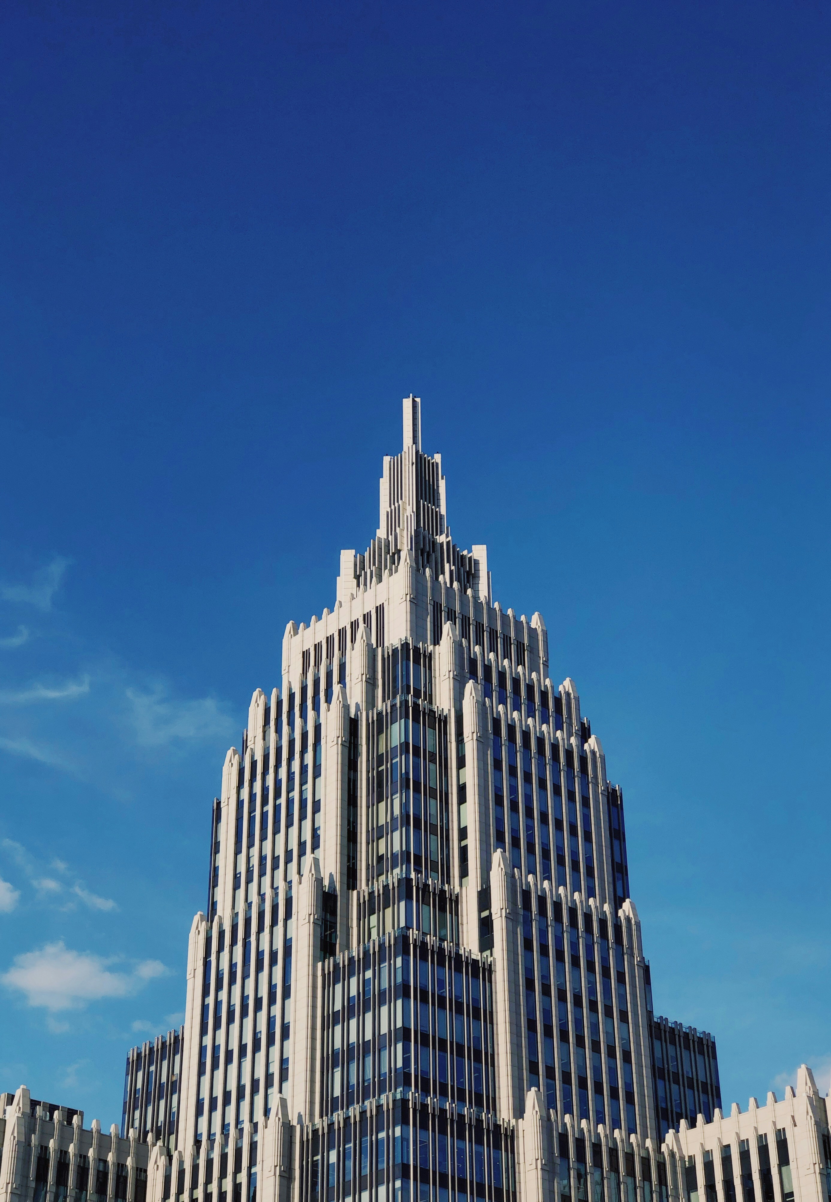 Art Deco skyscraper reaching towards the blue sky, showcasing intricate design and glass facades.