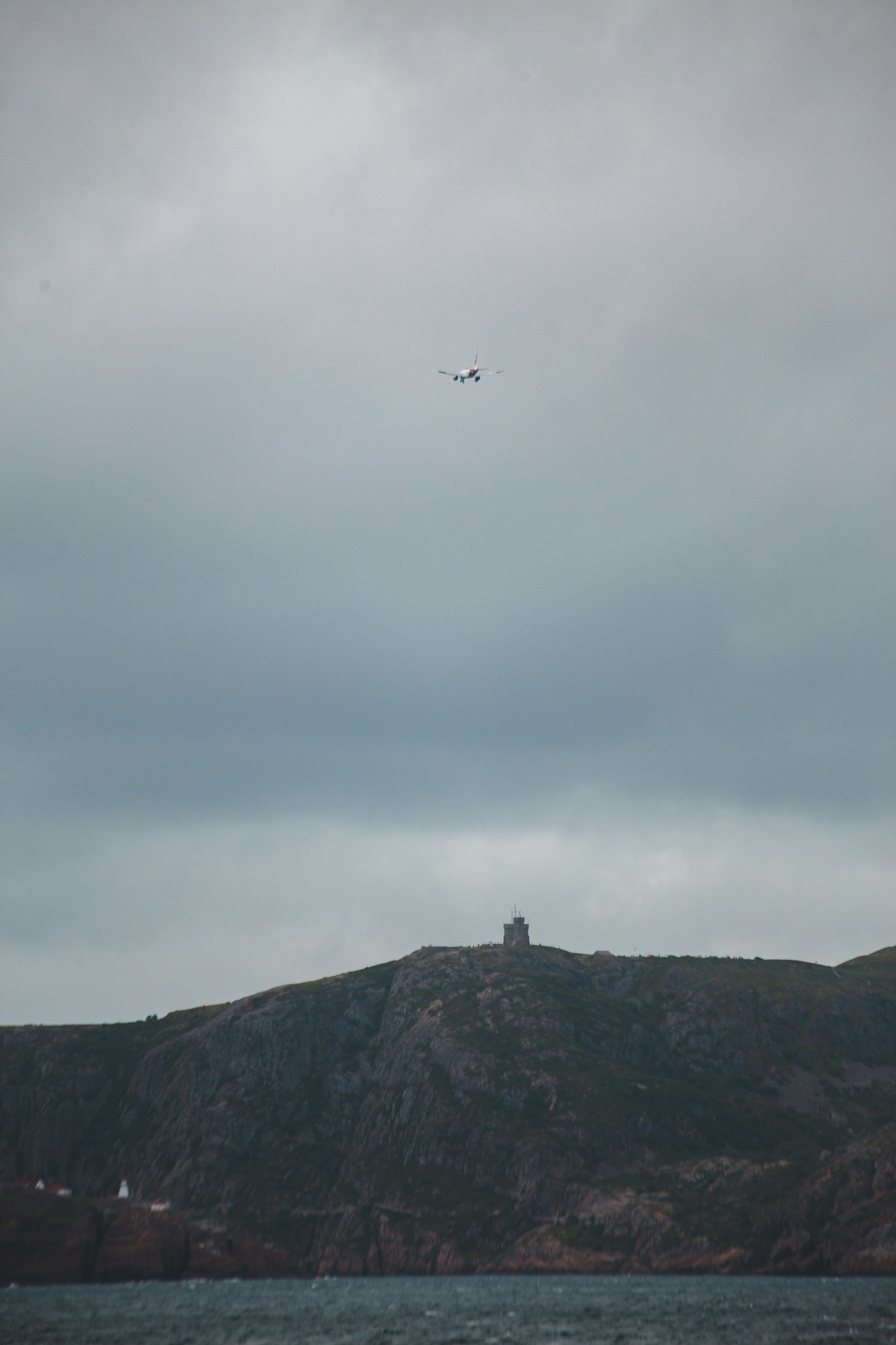 Speck of Flight Above a Rugged Coastal Promontory