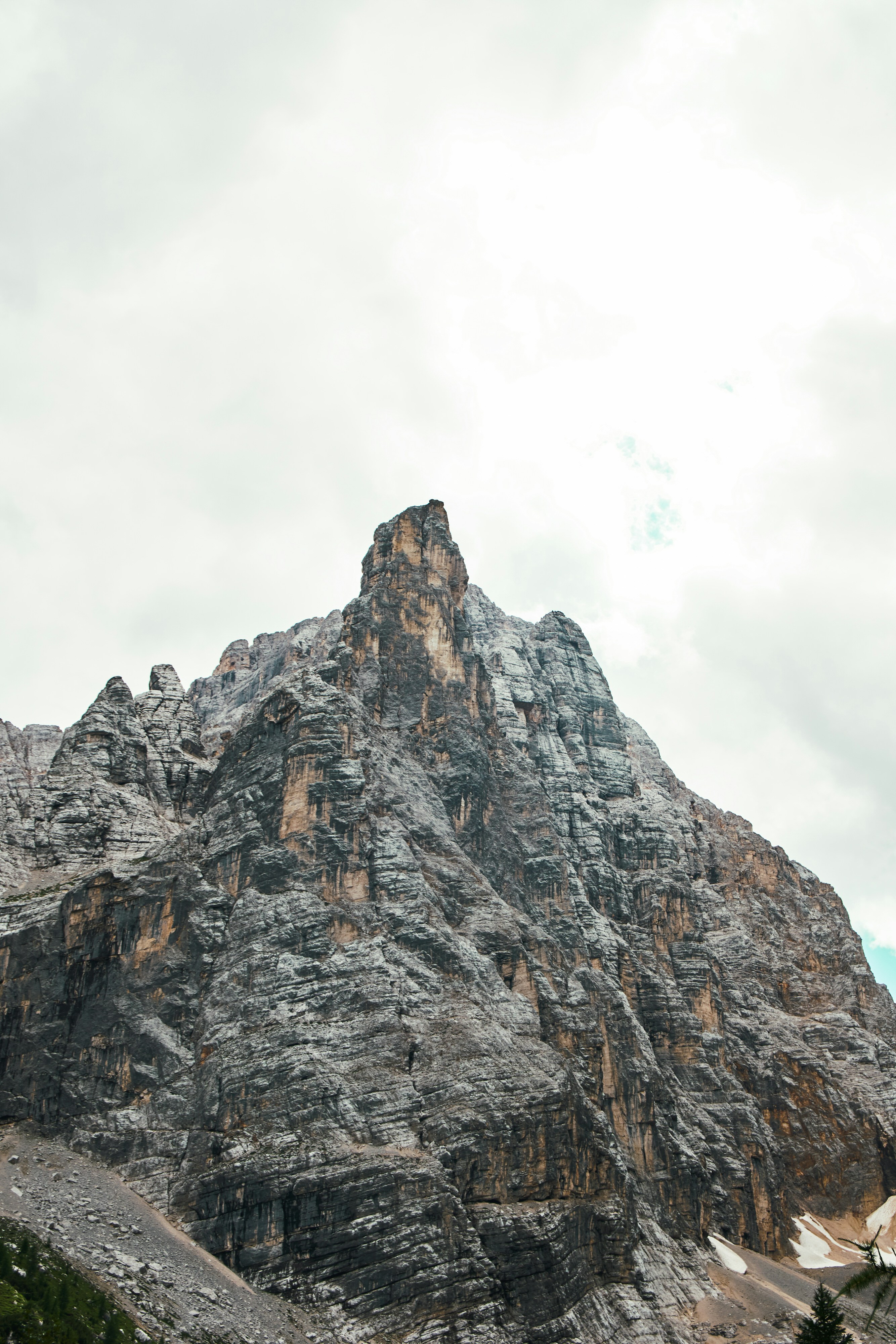 Towering rock formation of the Dolomites under a cloudy sky, showcasing the rugged beauty of the landscape.