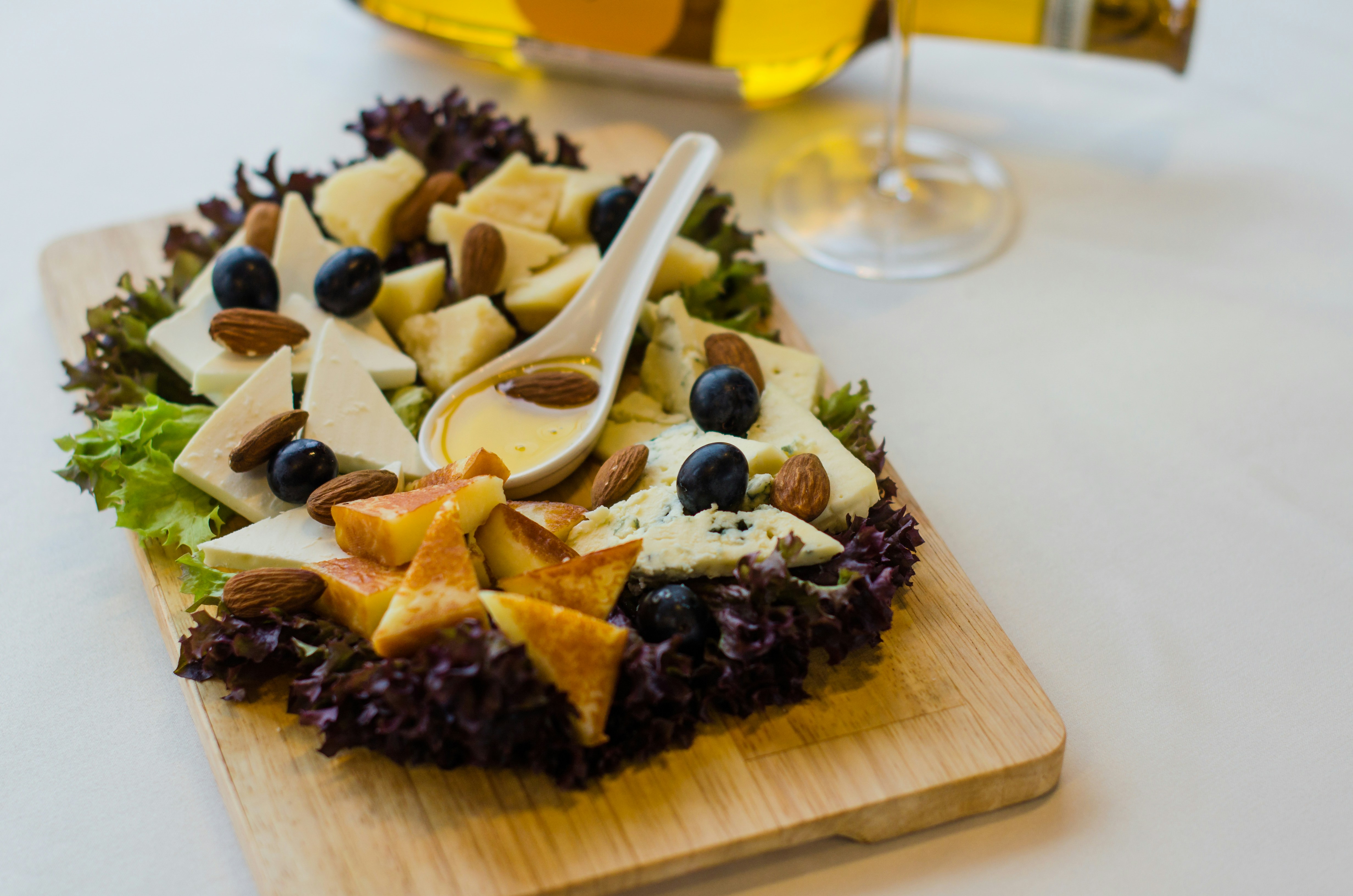 Cheese Cascade on a Wood Board Beneath a Glass of White Wine