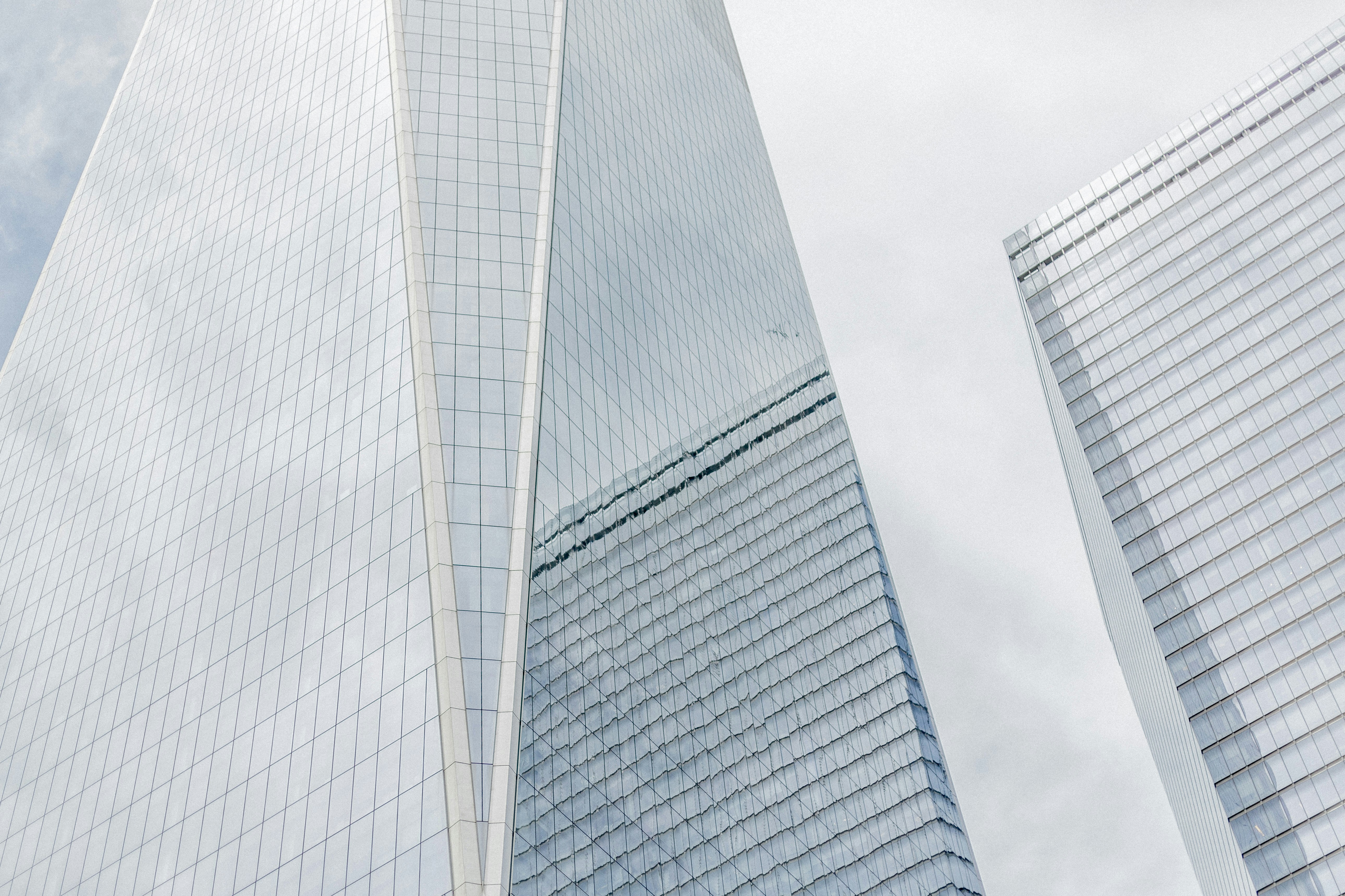 Skyscrapers with sleek glass facades reflect the cloudy sky, creating a geometric interplay of light and architecture.