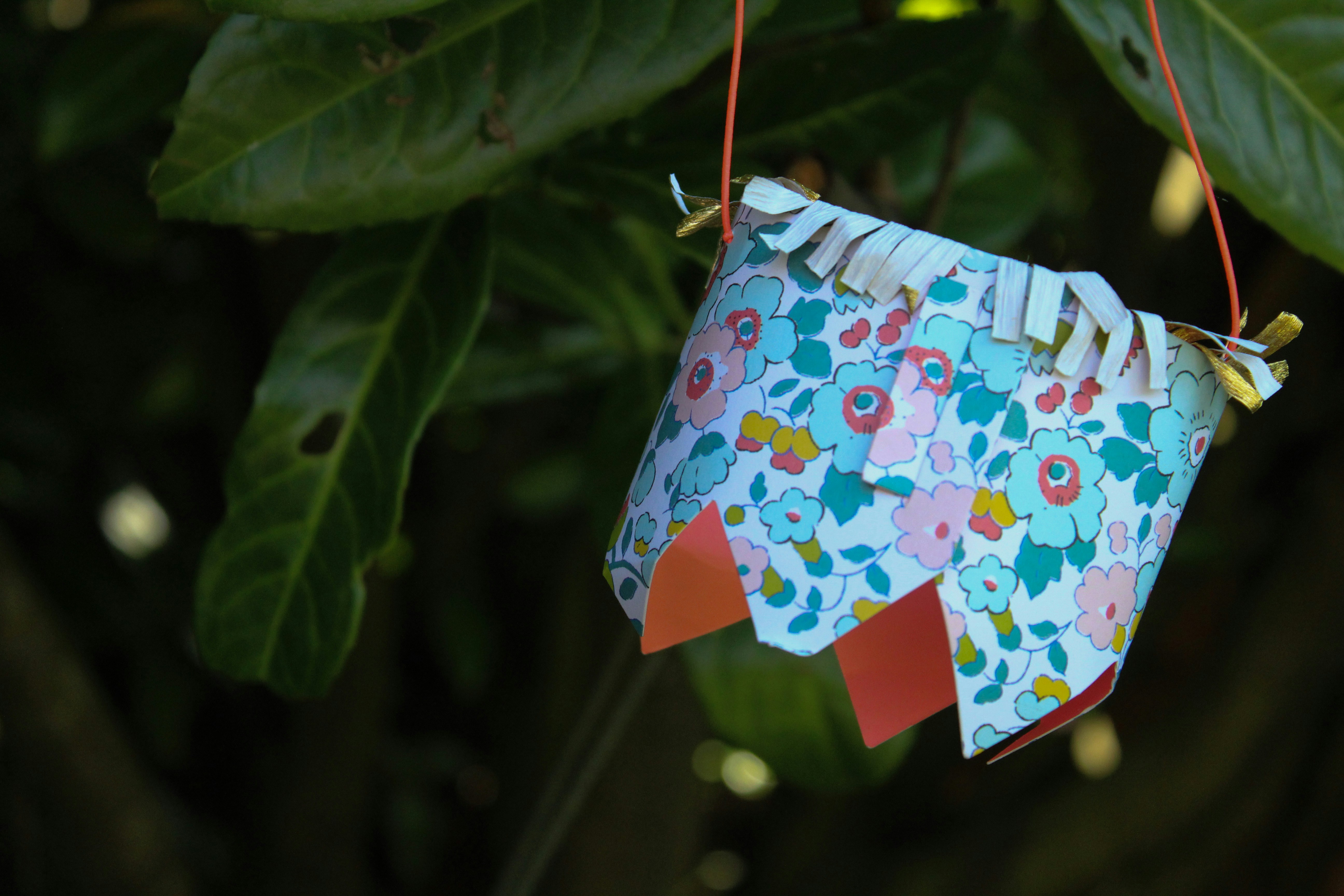 Pastel Floral Lantern Drifting Among Green Foliage