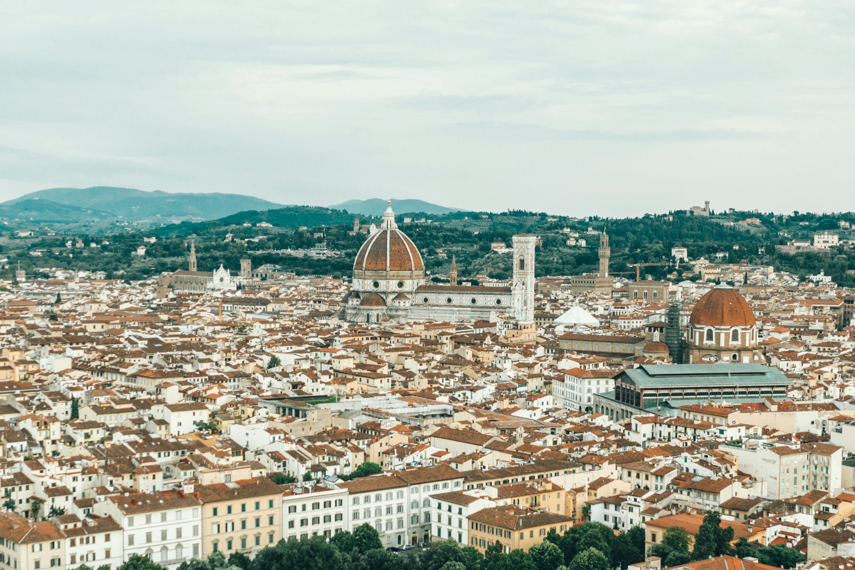 Aerial view of Florence's historic skyline with the iconic cathedral and distant rolling hills.