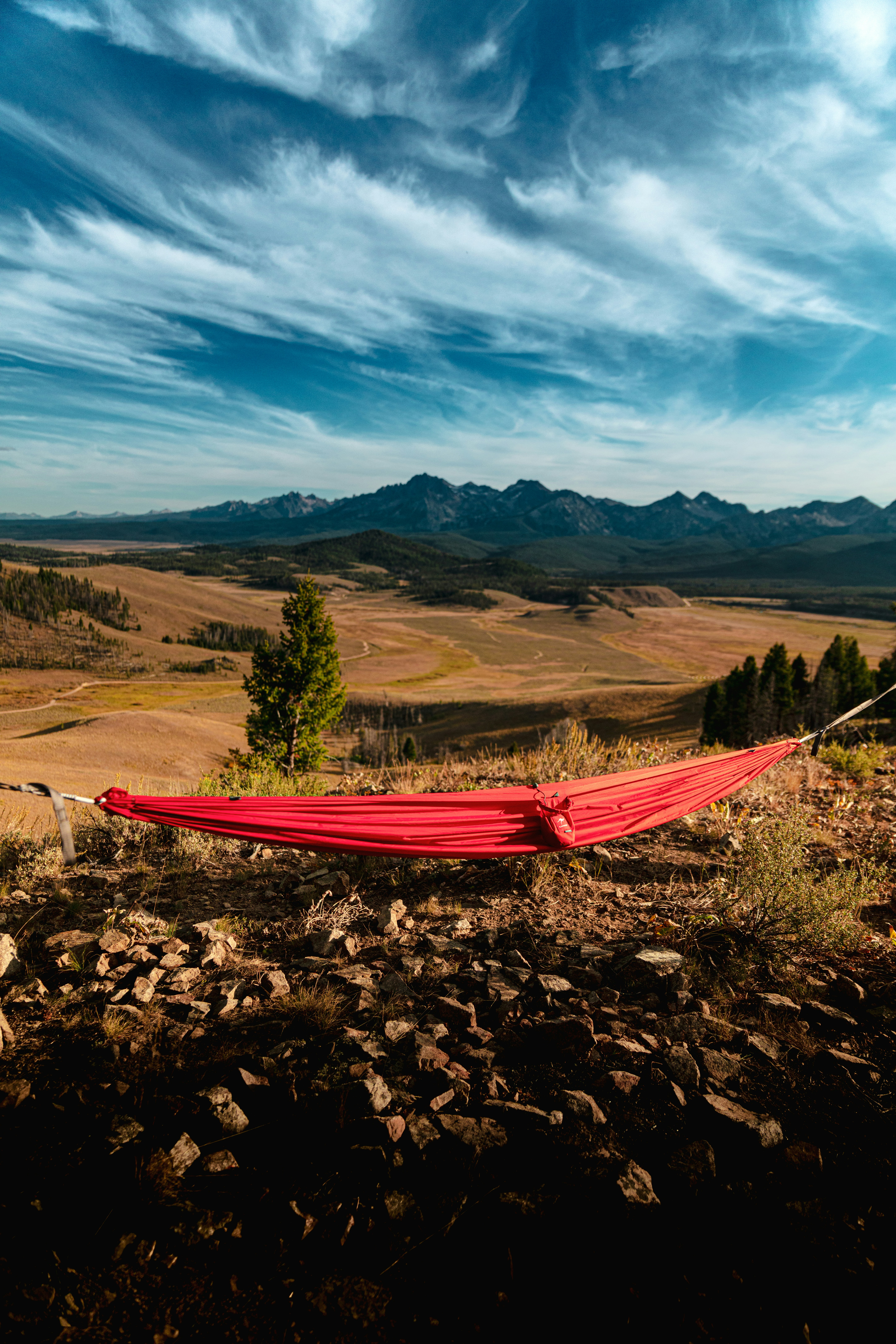 Red hammock on brown field viewing mountain under blue skies during ...