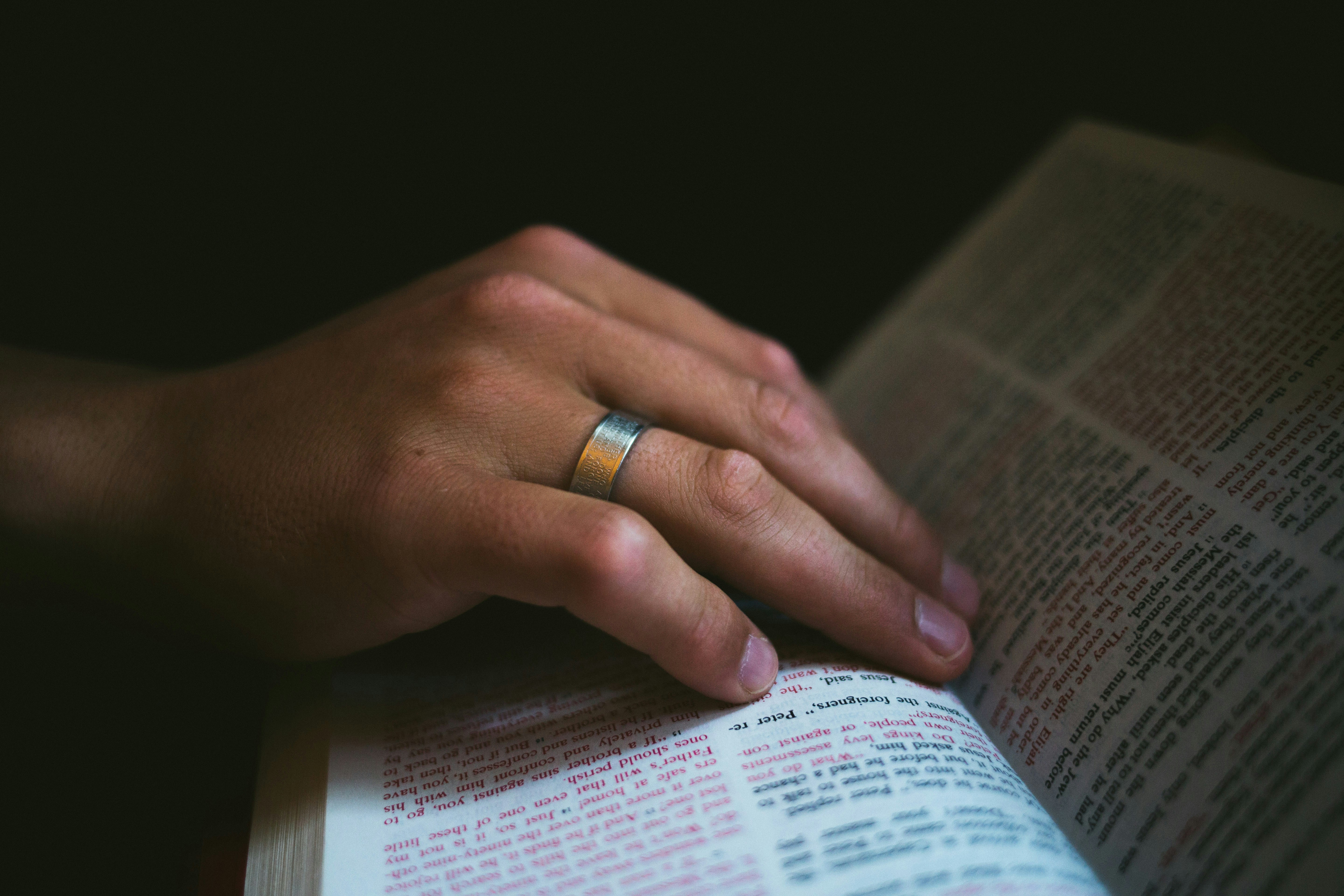 A person with a ring on their finger reading a book photo – Free Man ...