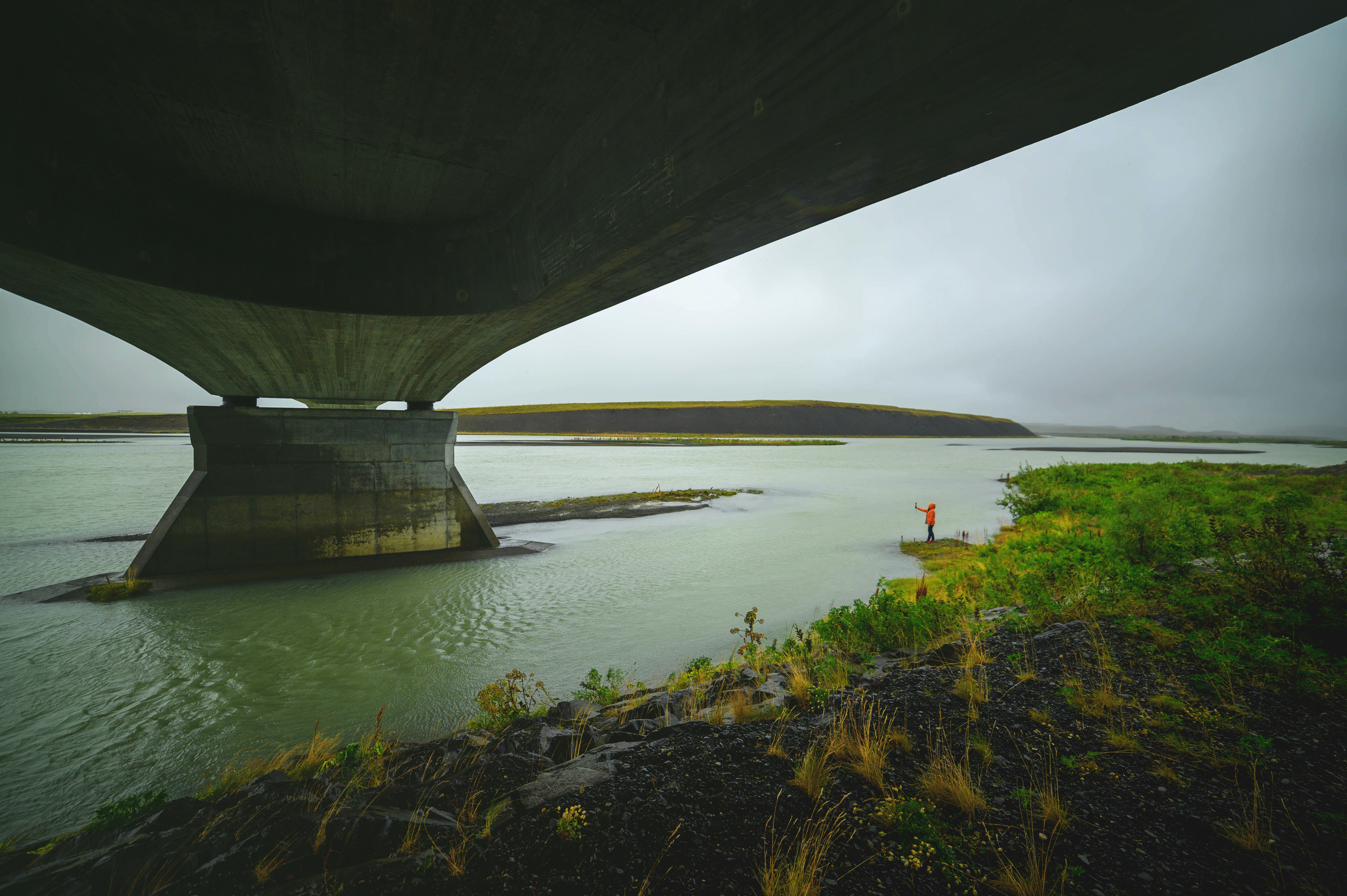 a person standing in the water under a bridge