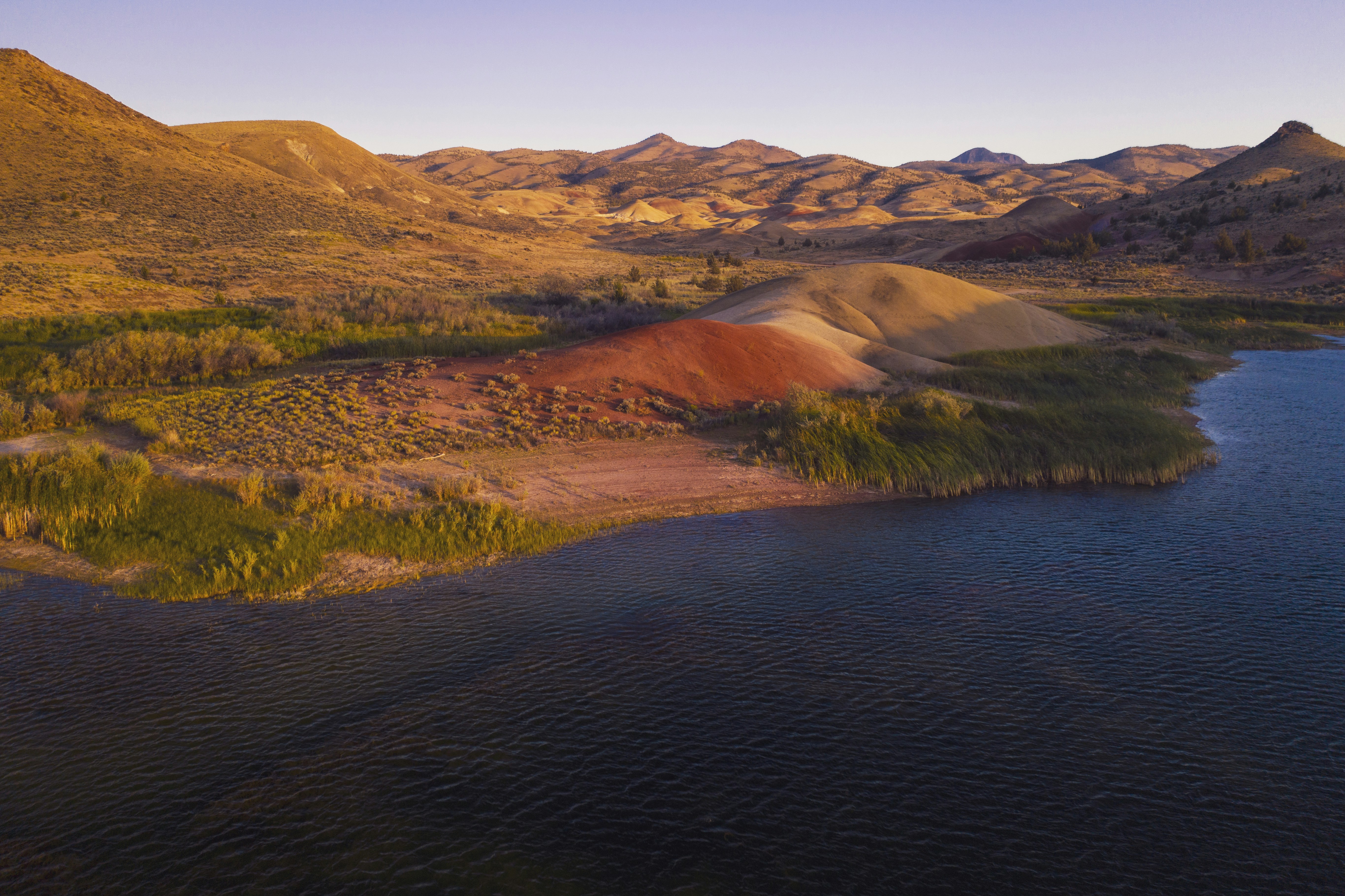 Red Dune Ridge Framed by a Luminous Lake at Golden Hour