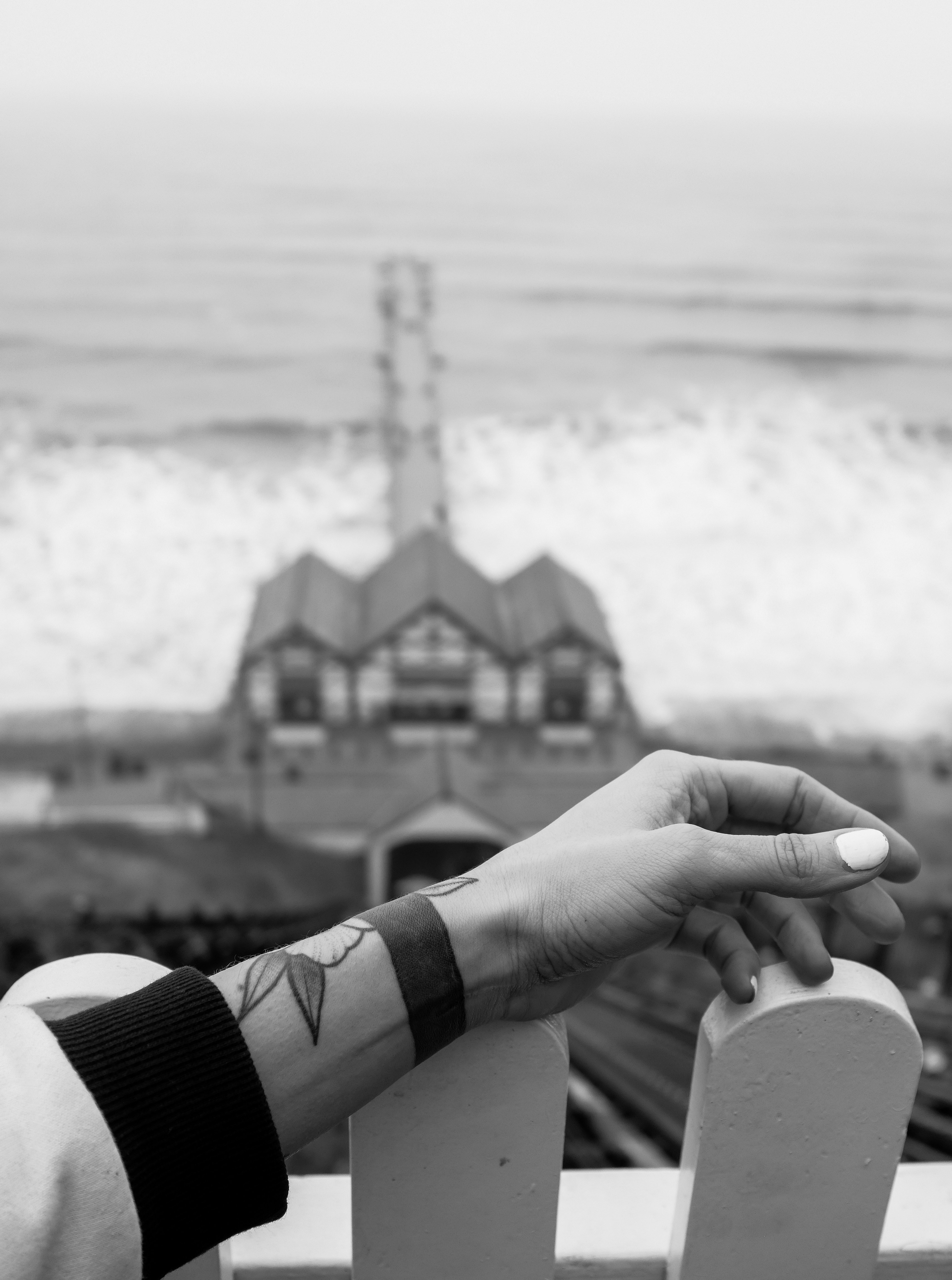Hand on the Rail: A Quiet View Over a Distant Pier