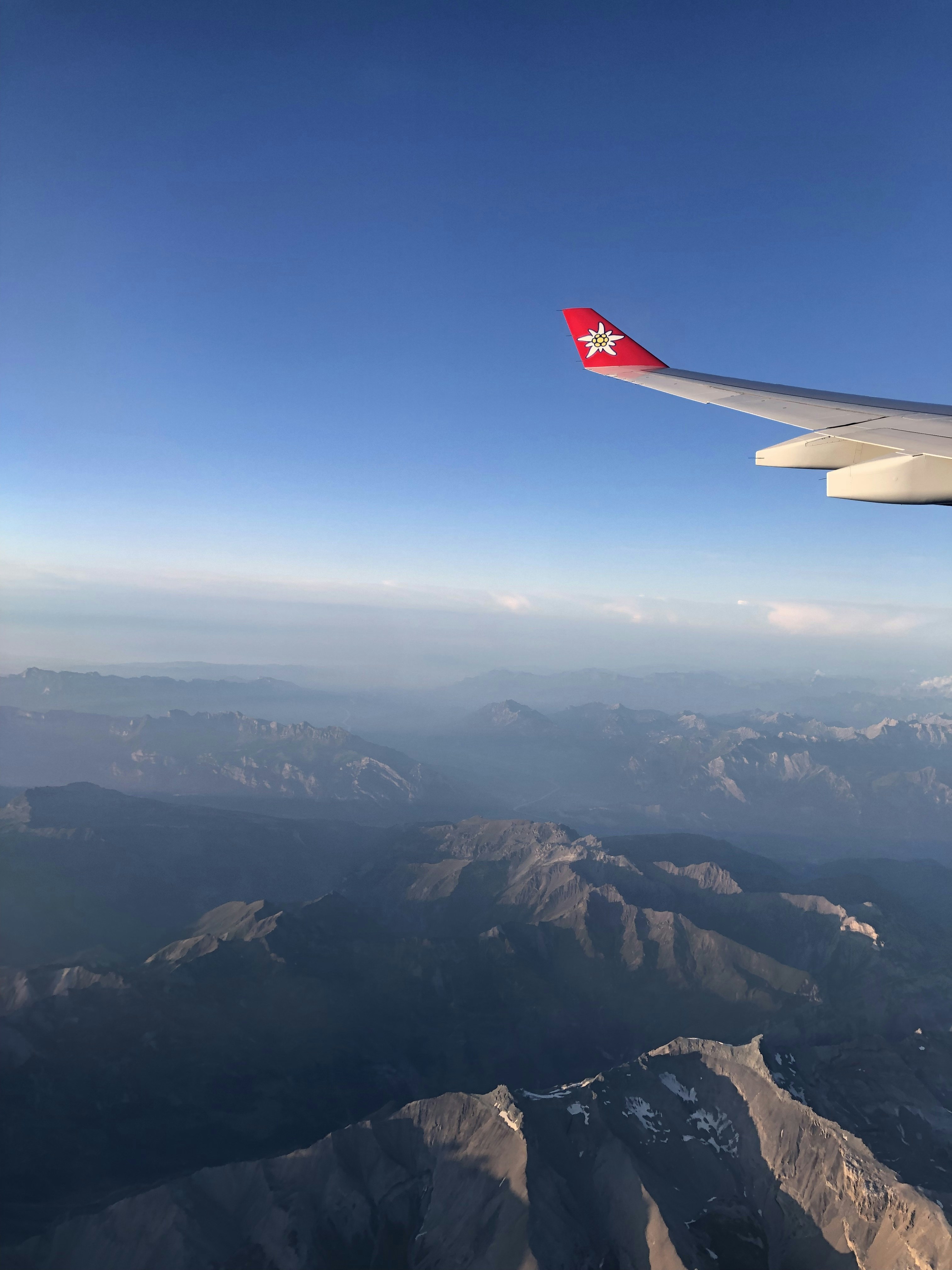 The wing of an airplane flying over a mountain range photo – Free Swiss ...
