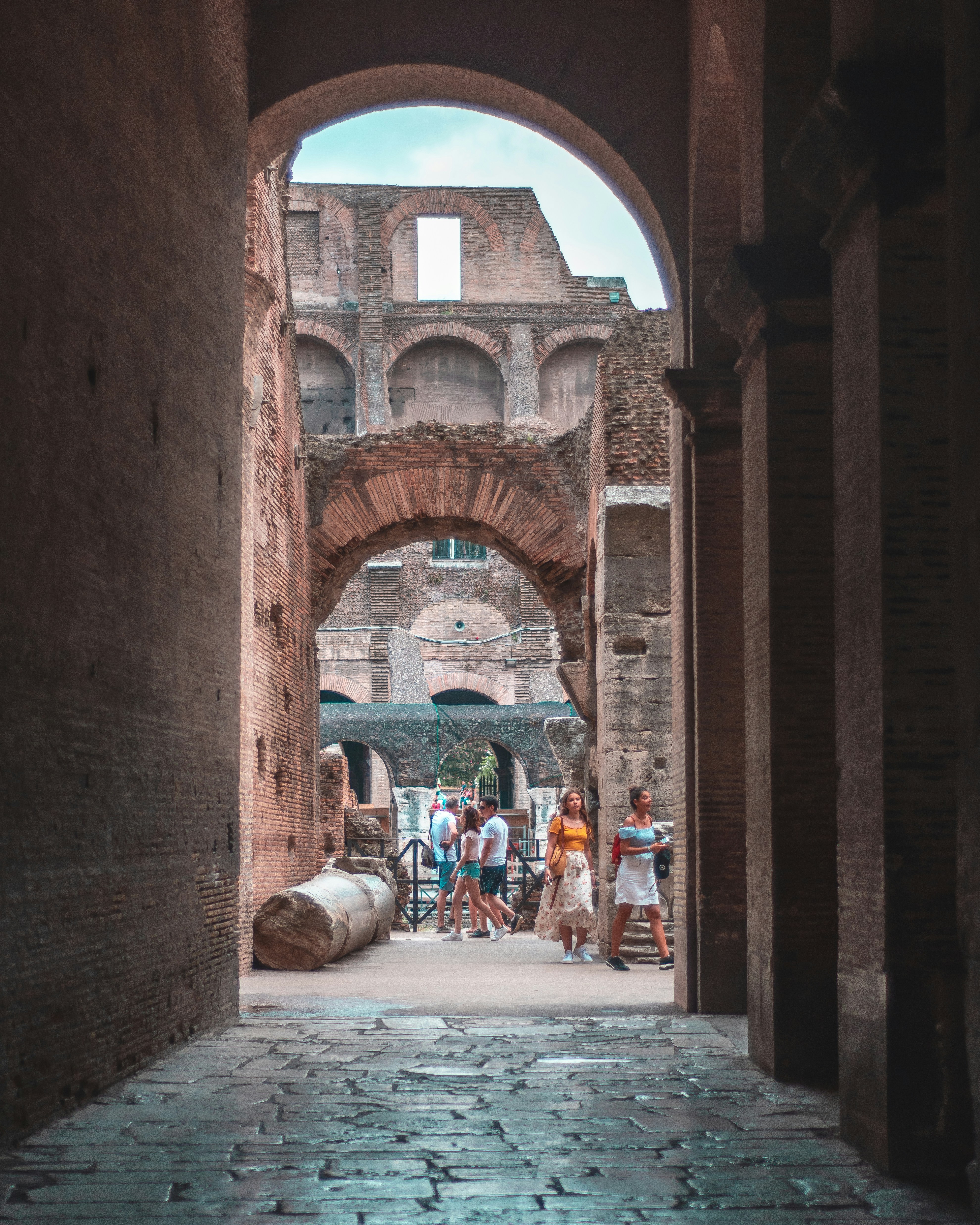 Visitors explore the remnants of a historic structure, framed by ancient arches and stone walls. The scene captures the blend of past and present in a timeless setting.