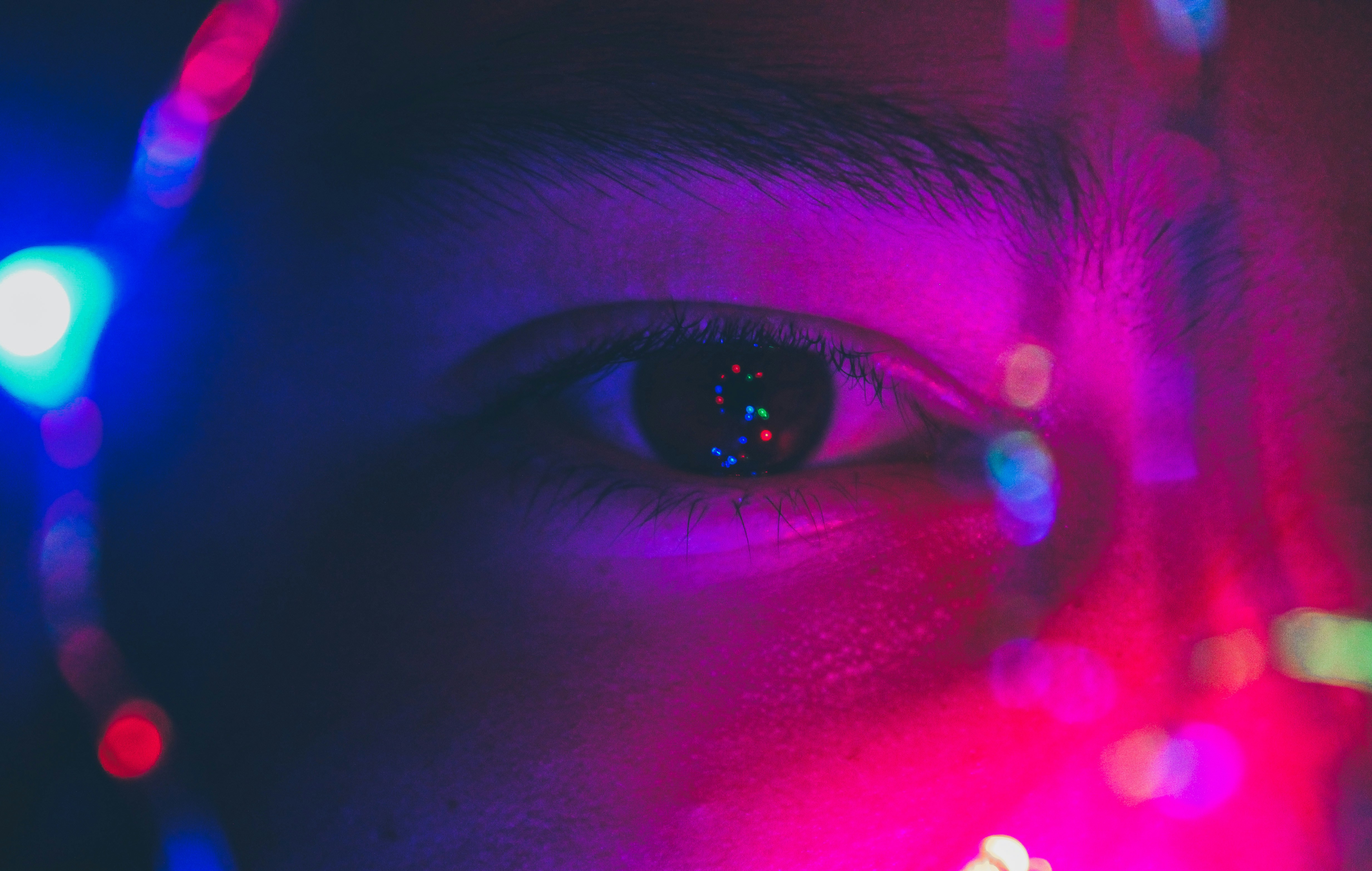 A close up of a person's eye with colored lights in the background ...