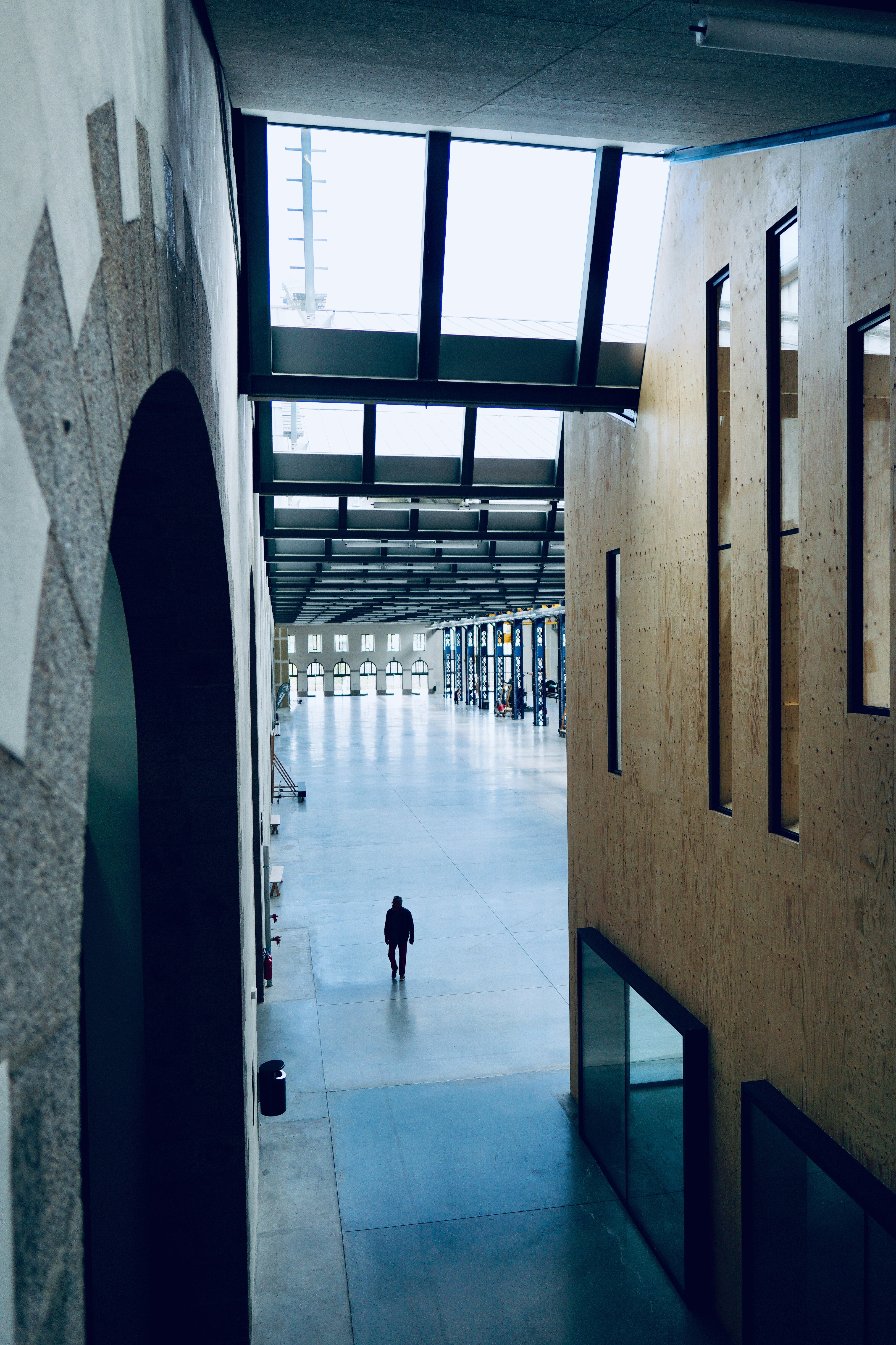 Lone silhouette along the axis of a glass-and-concrete atrium
