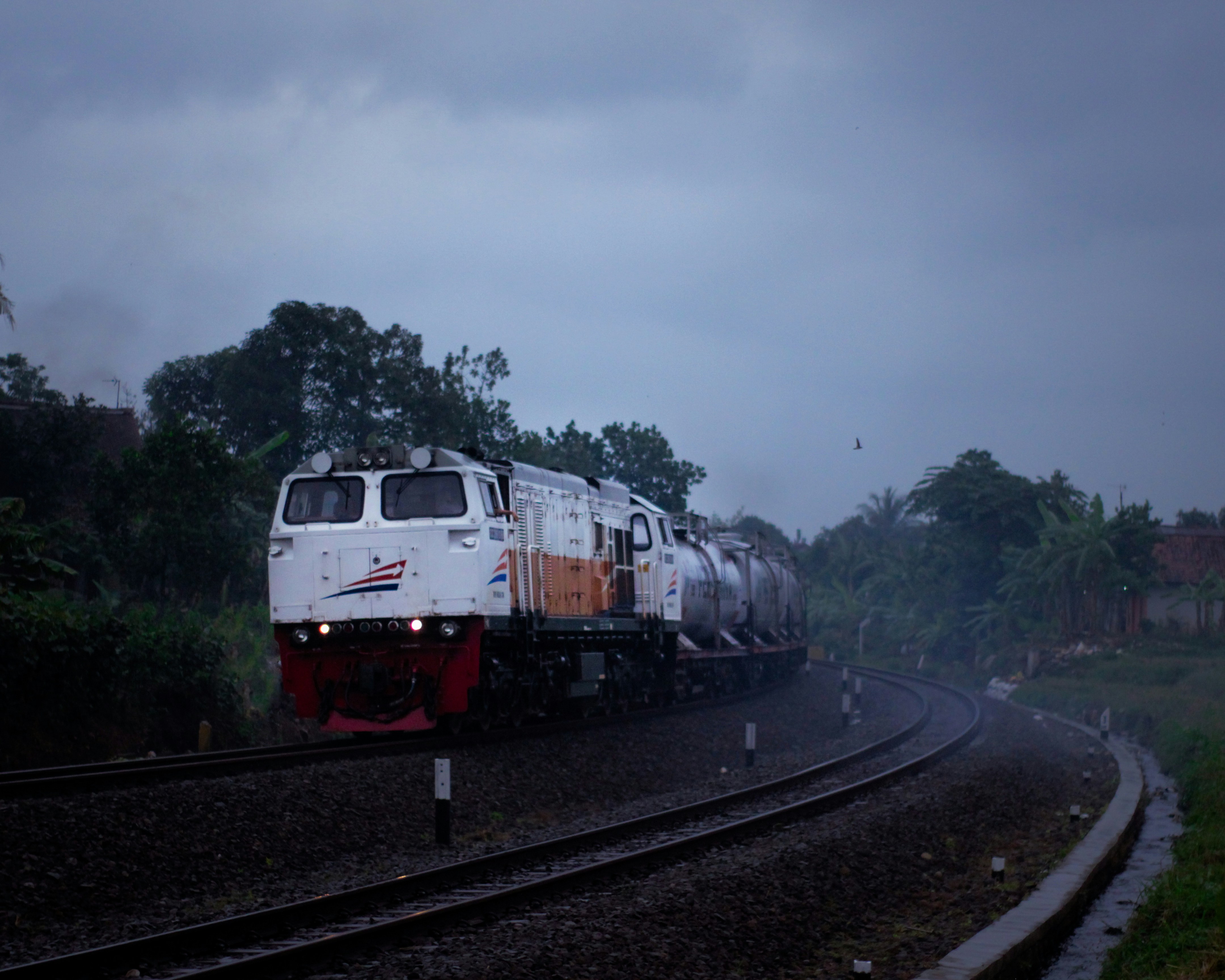 Train navigating curved tracks under overcast skies in Central Java.