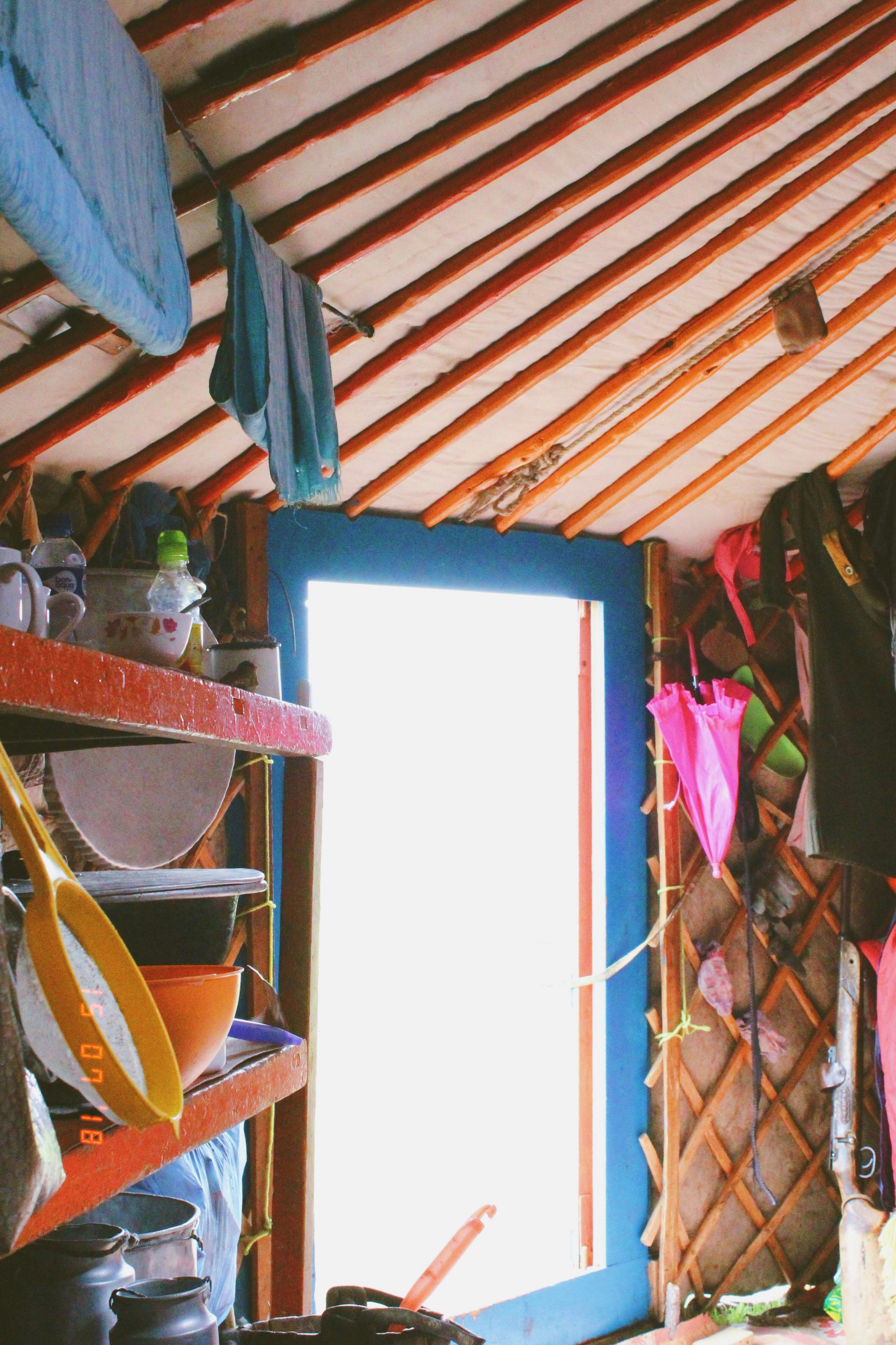 Cozy shed kitchen: hanging laundry and colorful utensils within a warm, sunlit doorway