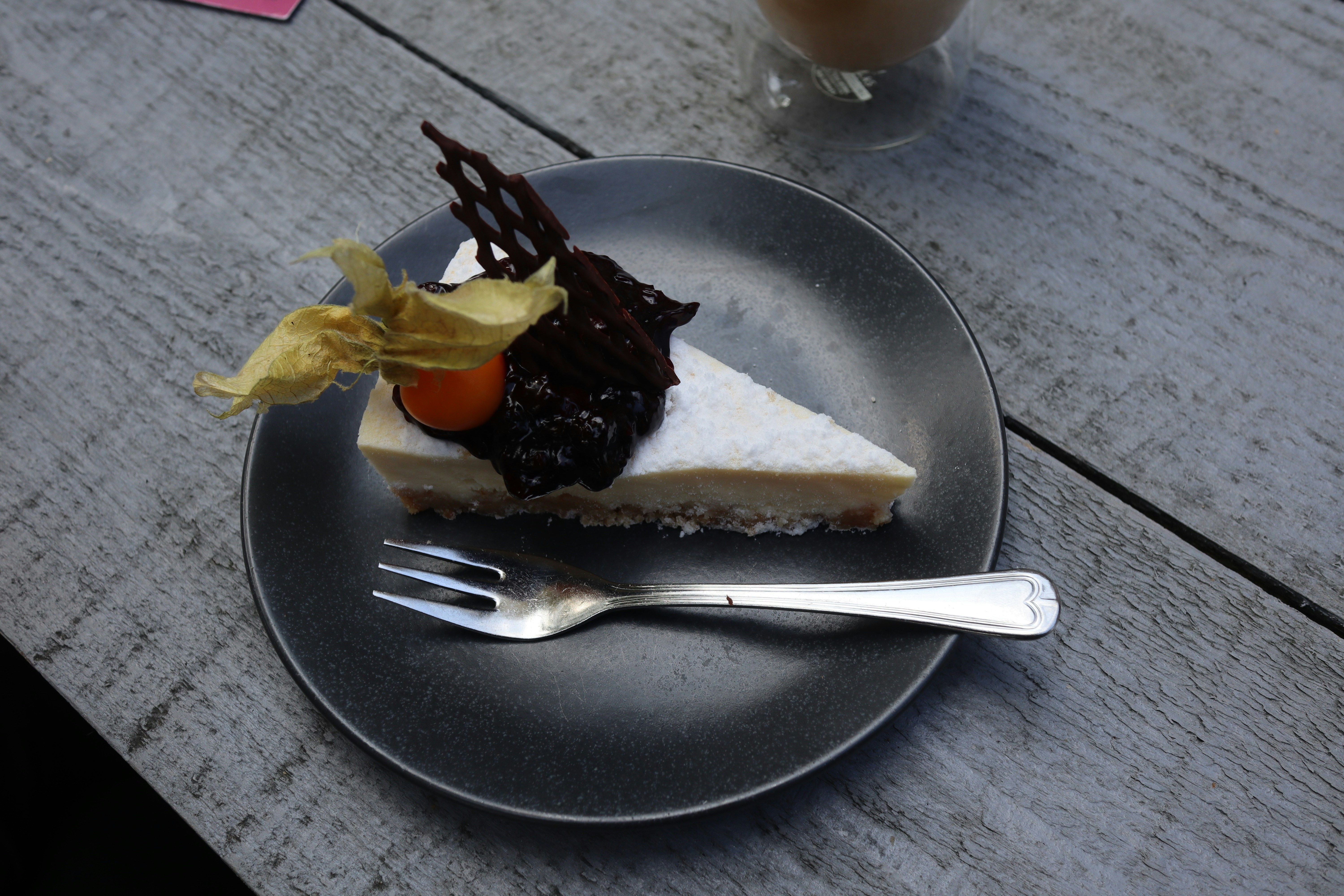 Cheesecake Slice on a Weathered Wood Table with Chocolate Lace
