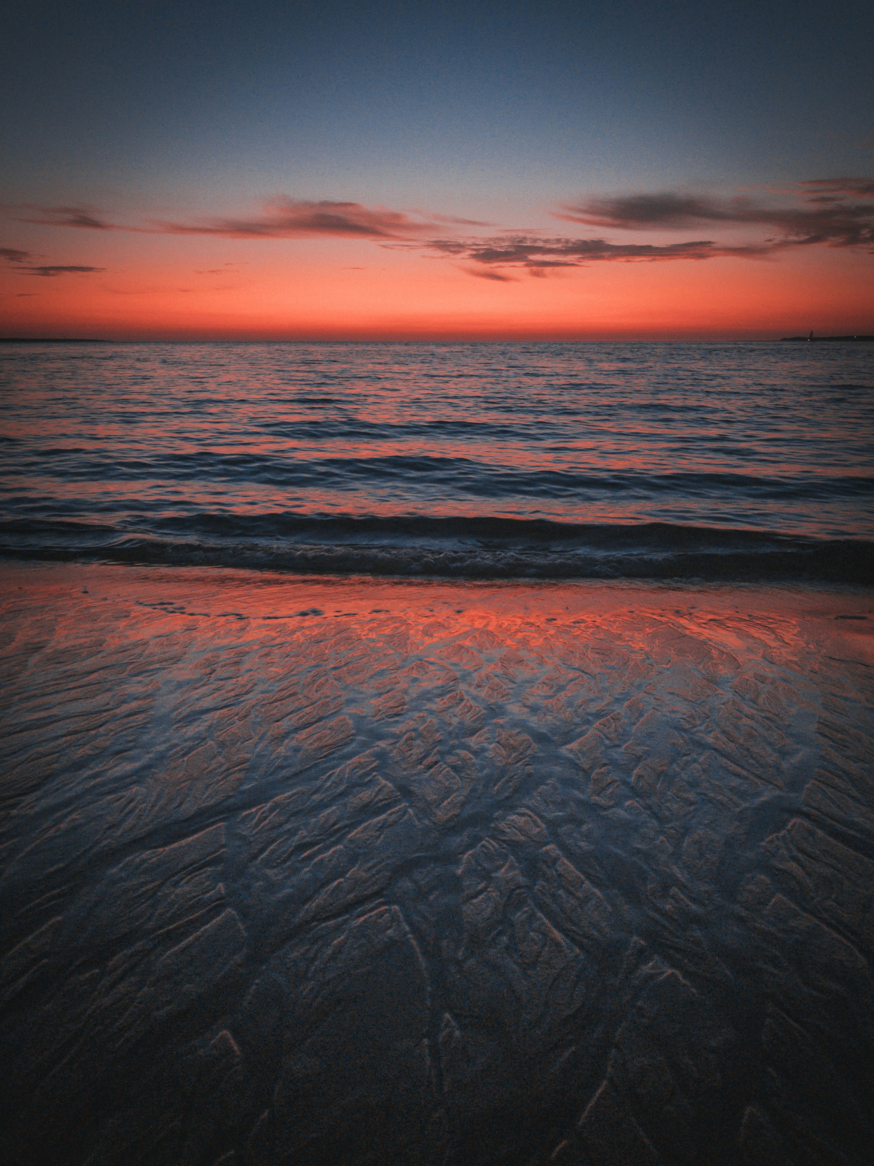 Crimson Horizon over Textured Sand and Quiet Waves at Dusk