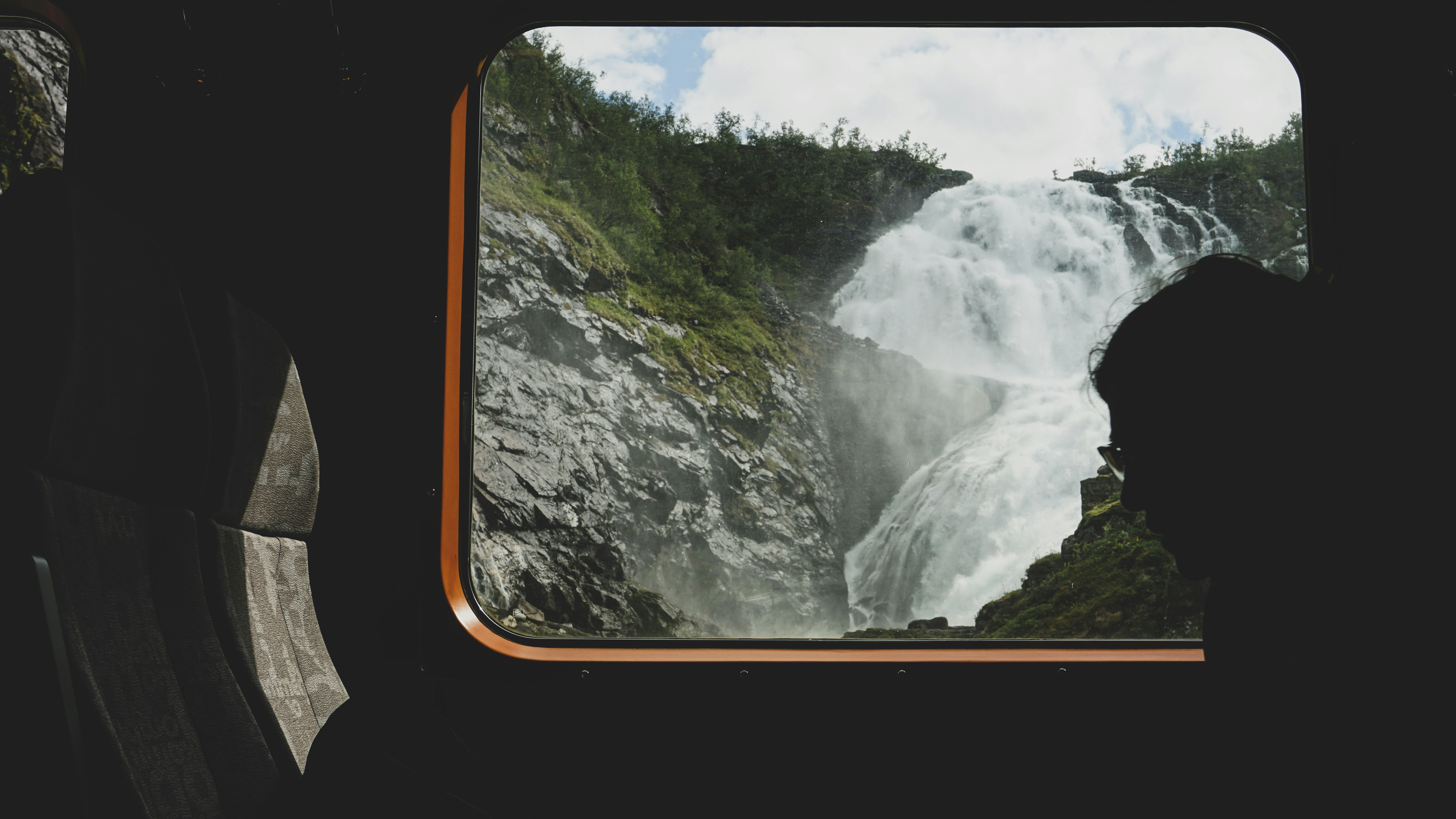 Orange Frame, Green Gorge: Waterfall View from a Vehicle Window
