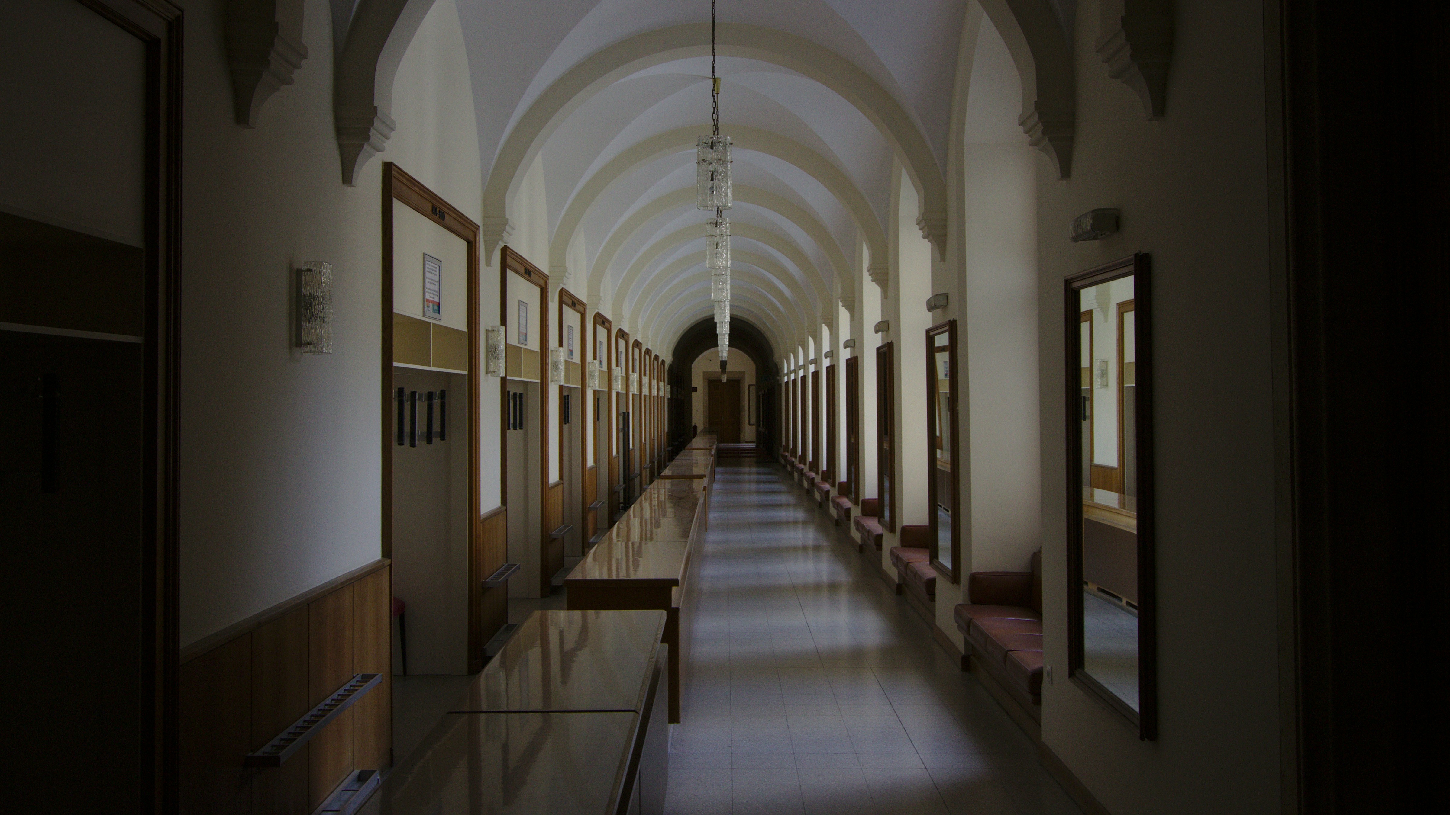 Long, dimly lit corridor with arched ceilings and mirrored walls, evoking a sense of nostalgia and quiet reflection.