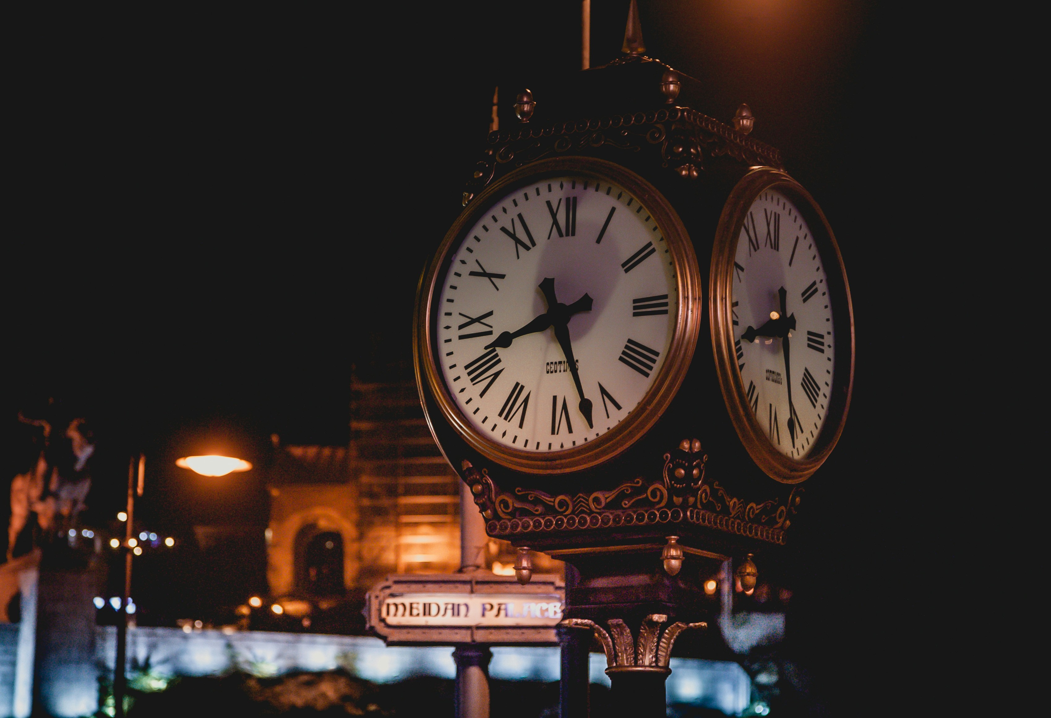 Black and brass numeral clock on street during night time photo – Free ...