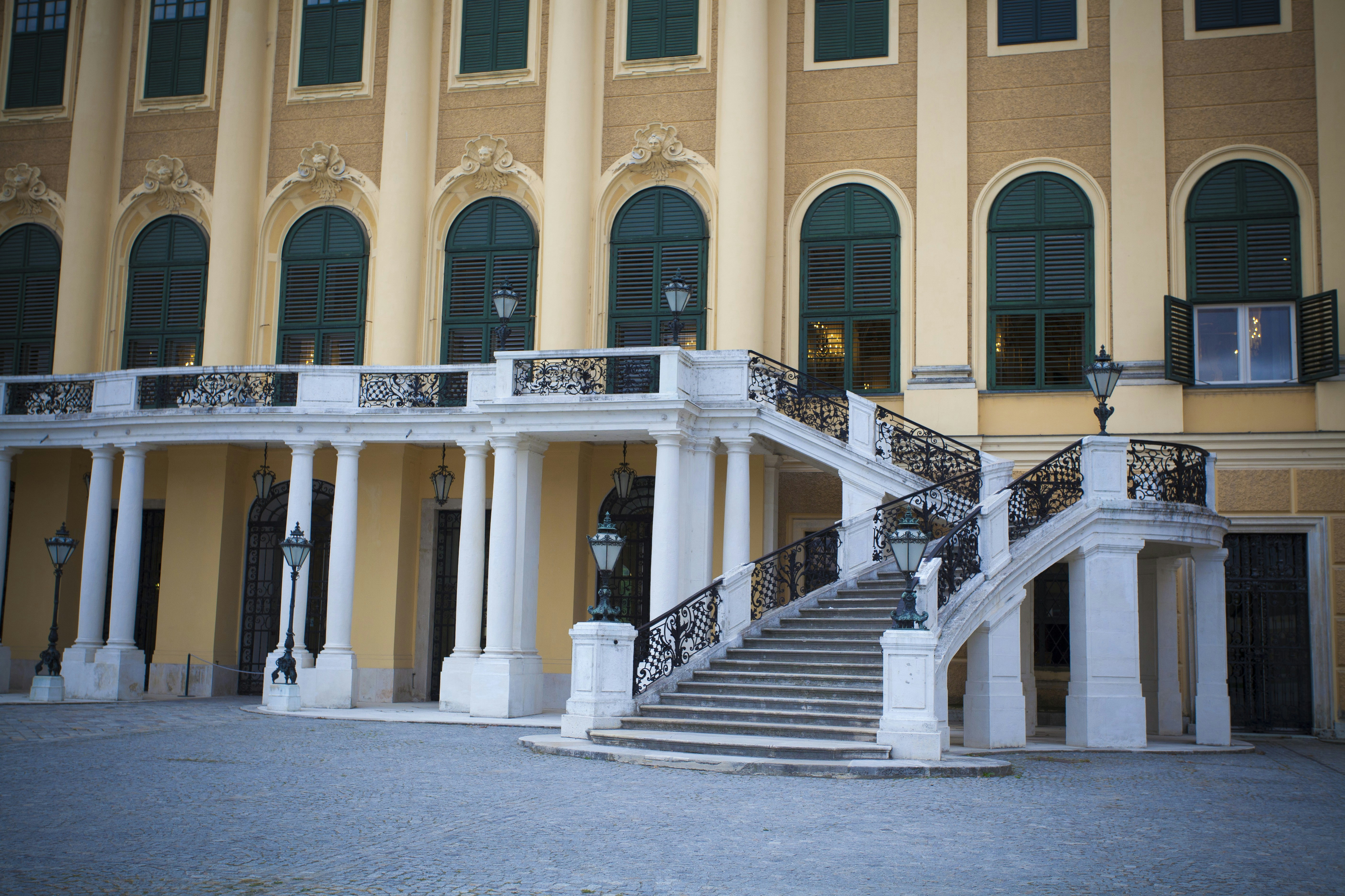 Ornate staircase leading to arched windows on a historic Baroque building facade.
