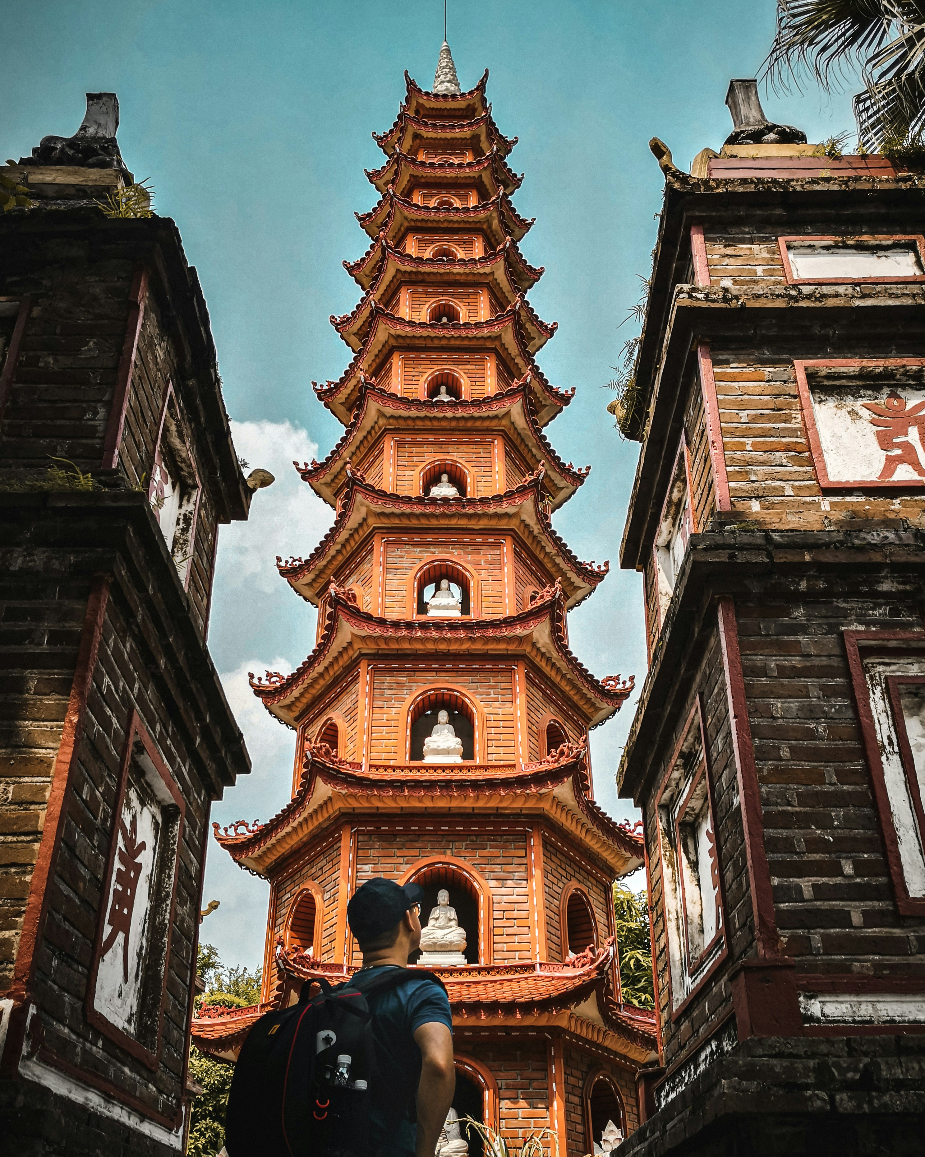 A traveler stands before a towering pagoda framed by ancient stone structures, evoking a sense of serenity and exploration.