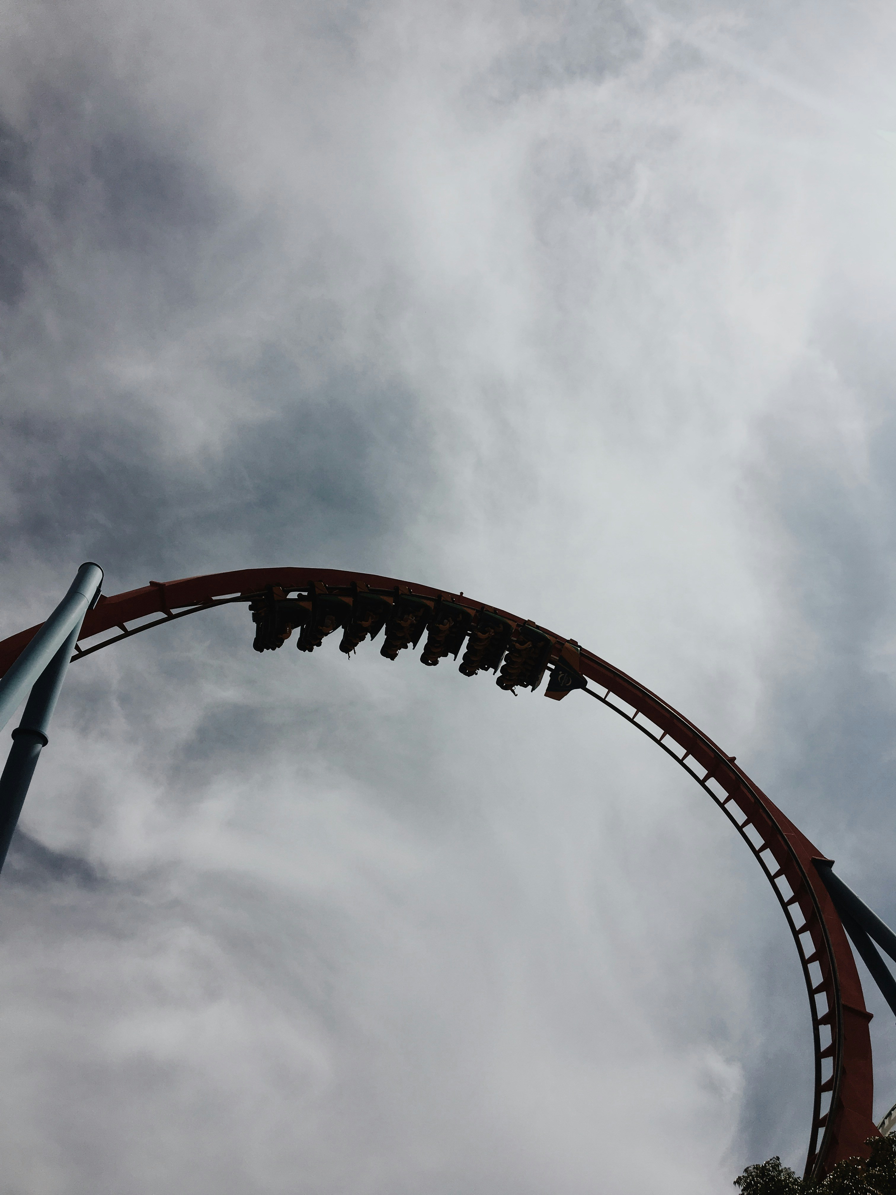 Roller coaster ascending in a dramatic arc against a cloudy sky, capturing the essence of excitement and thrill.