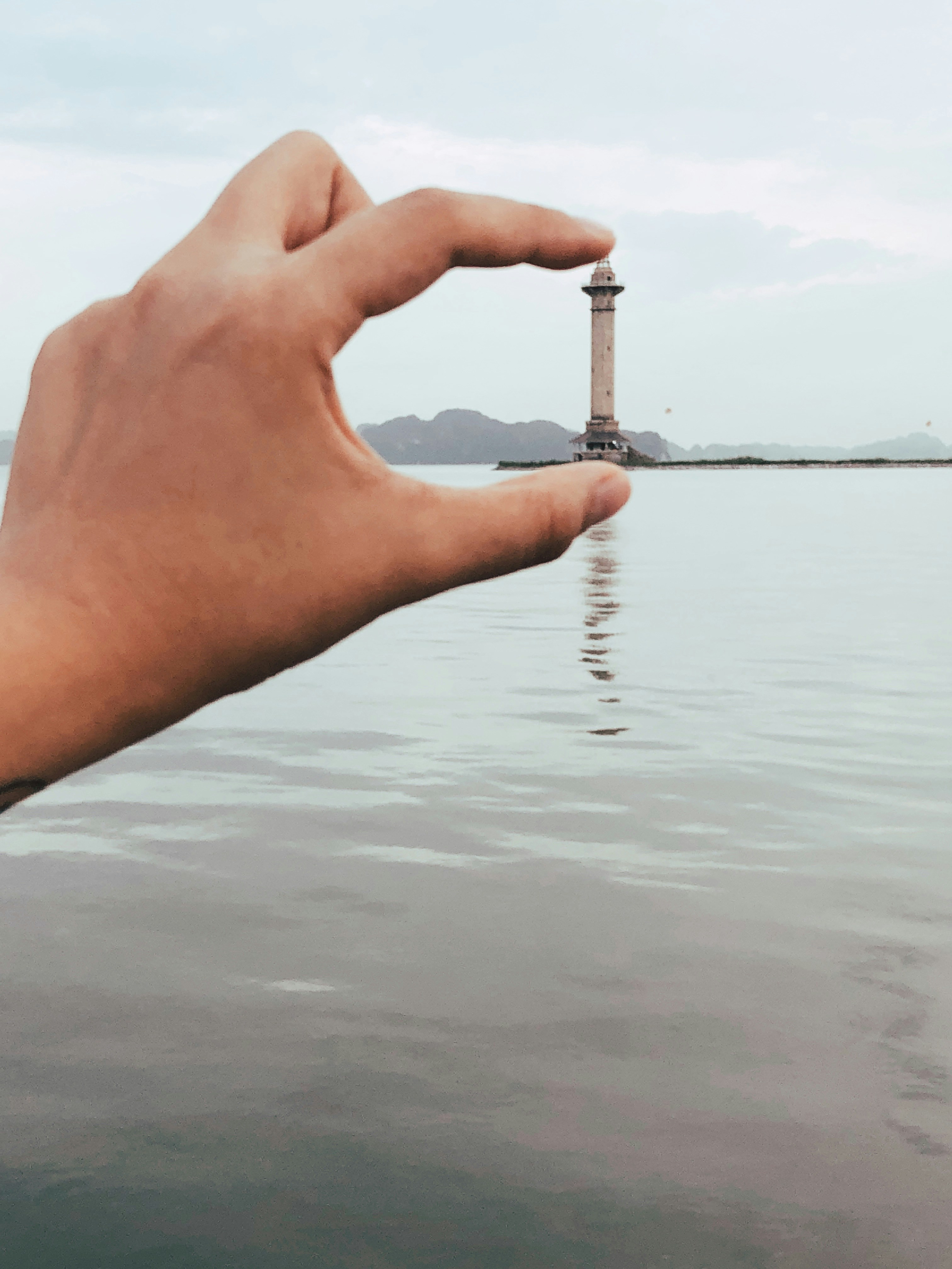 Pinched Horizon: A Lighthouse Framed by a Gentle Hand