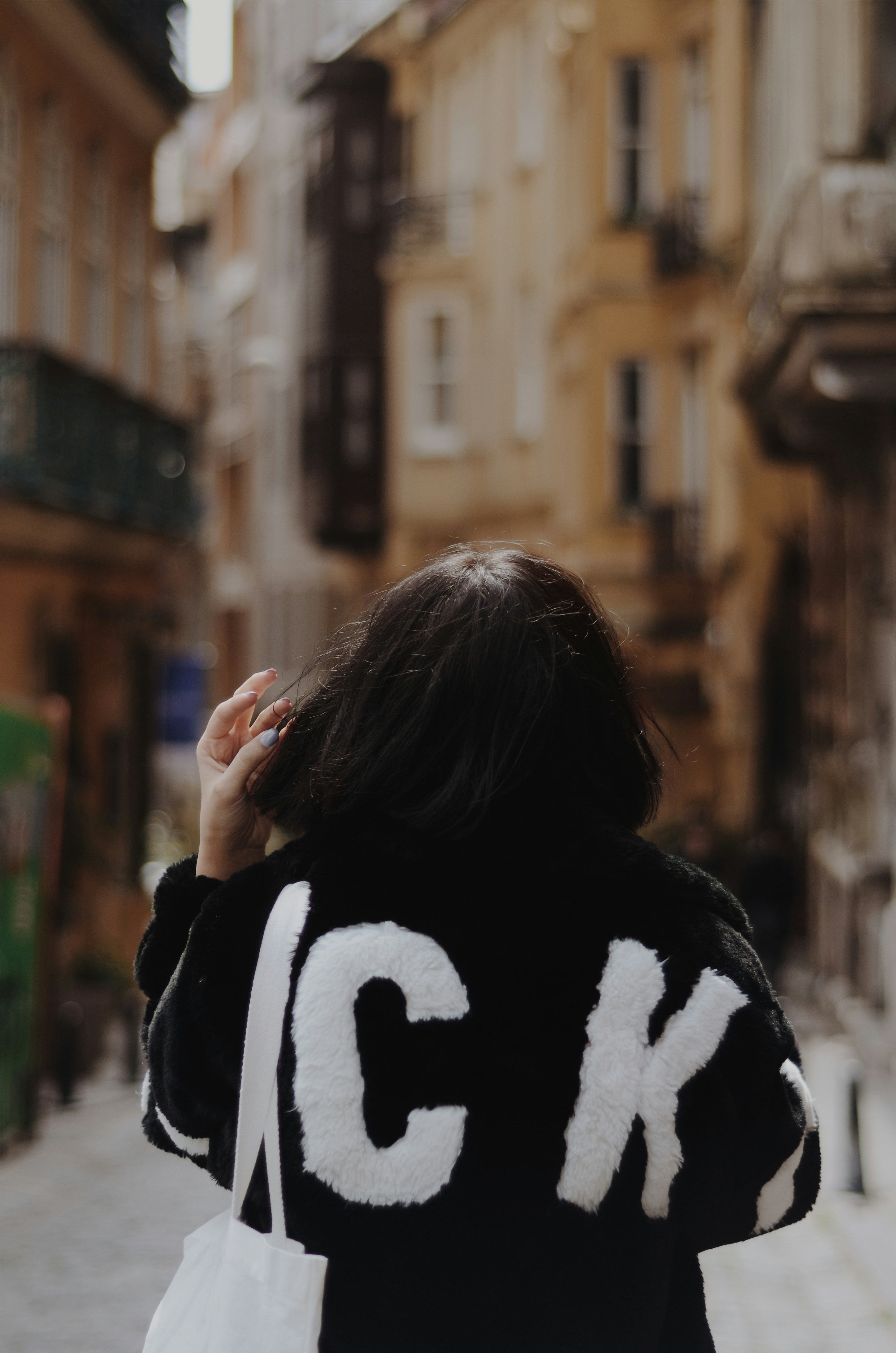 Misted Street, Anonymous Moment: A Woman in Black with White Letters Walking Away