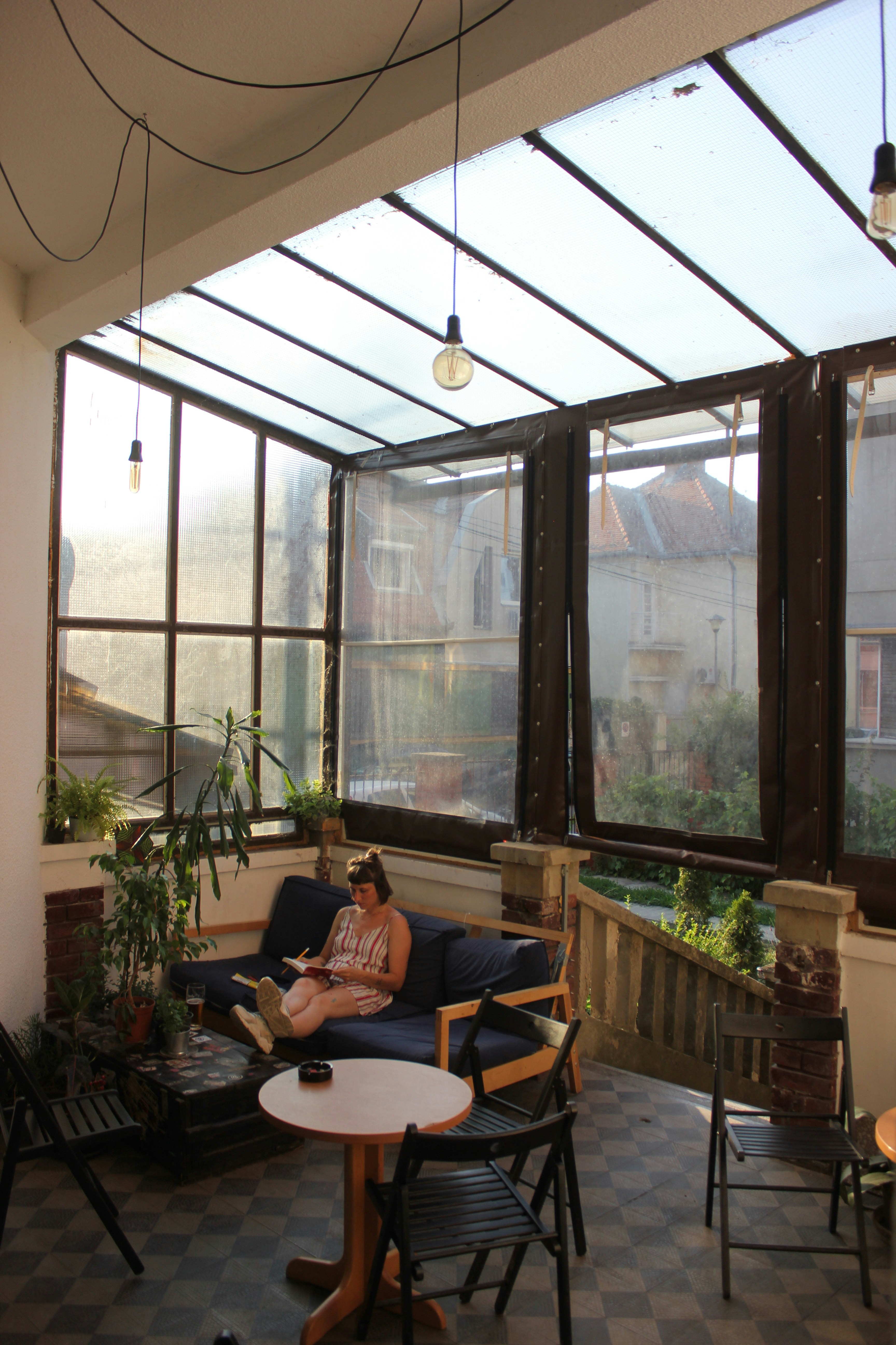 Sunlit Conservatory Nook: A Reader Finds Solace on a Cushioned Sofa