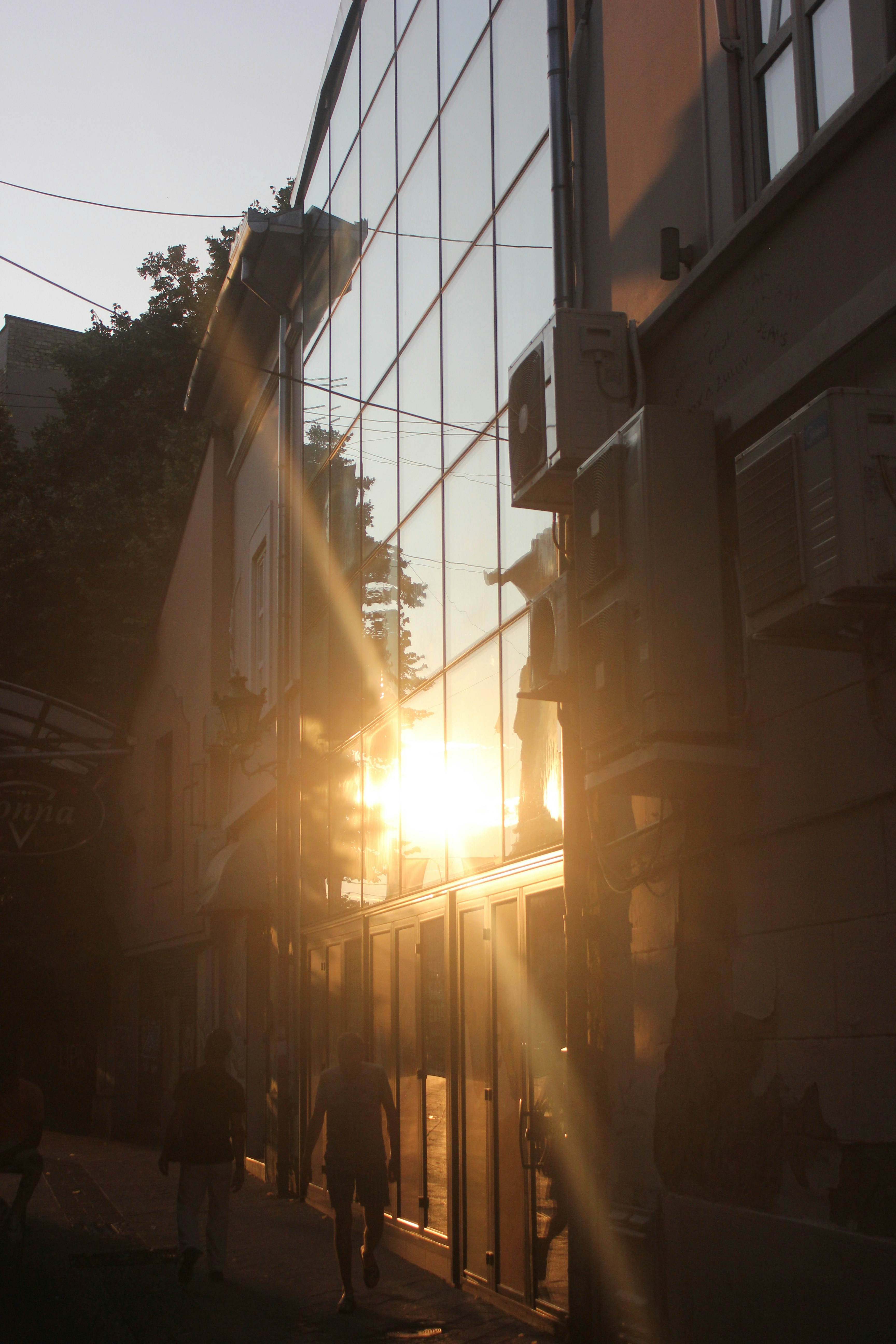 Sunburst Through Glass and Street: Evening Walk in a Glassy Alley