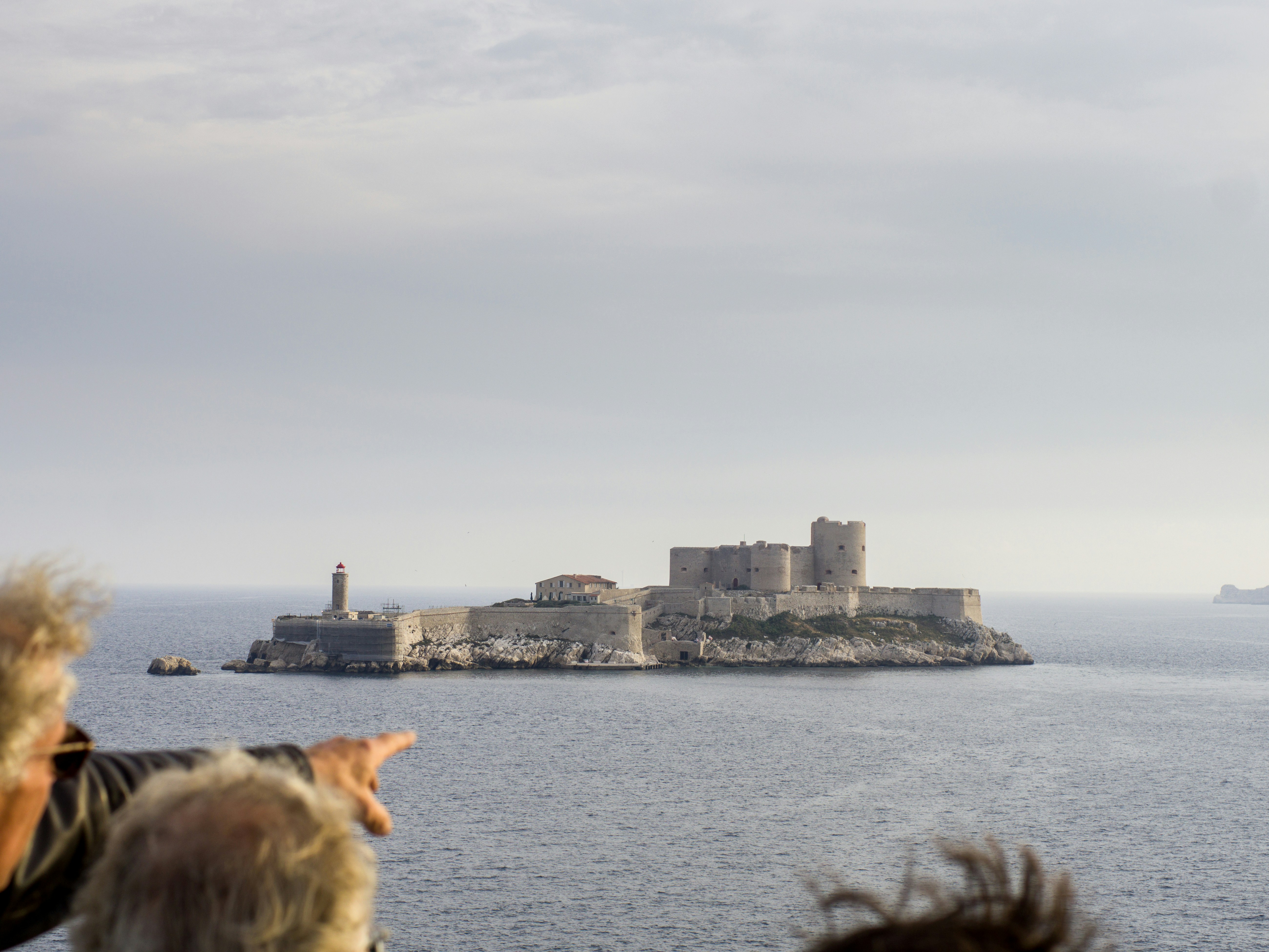 Tourists pointing towards a historic castle on an island surrounded by water.