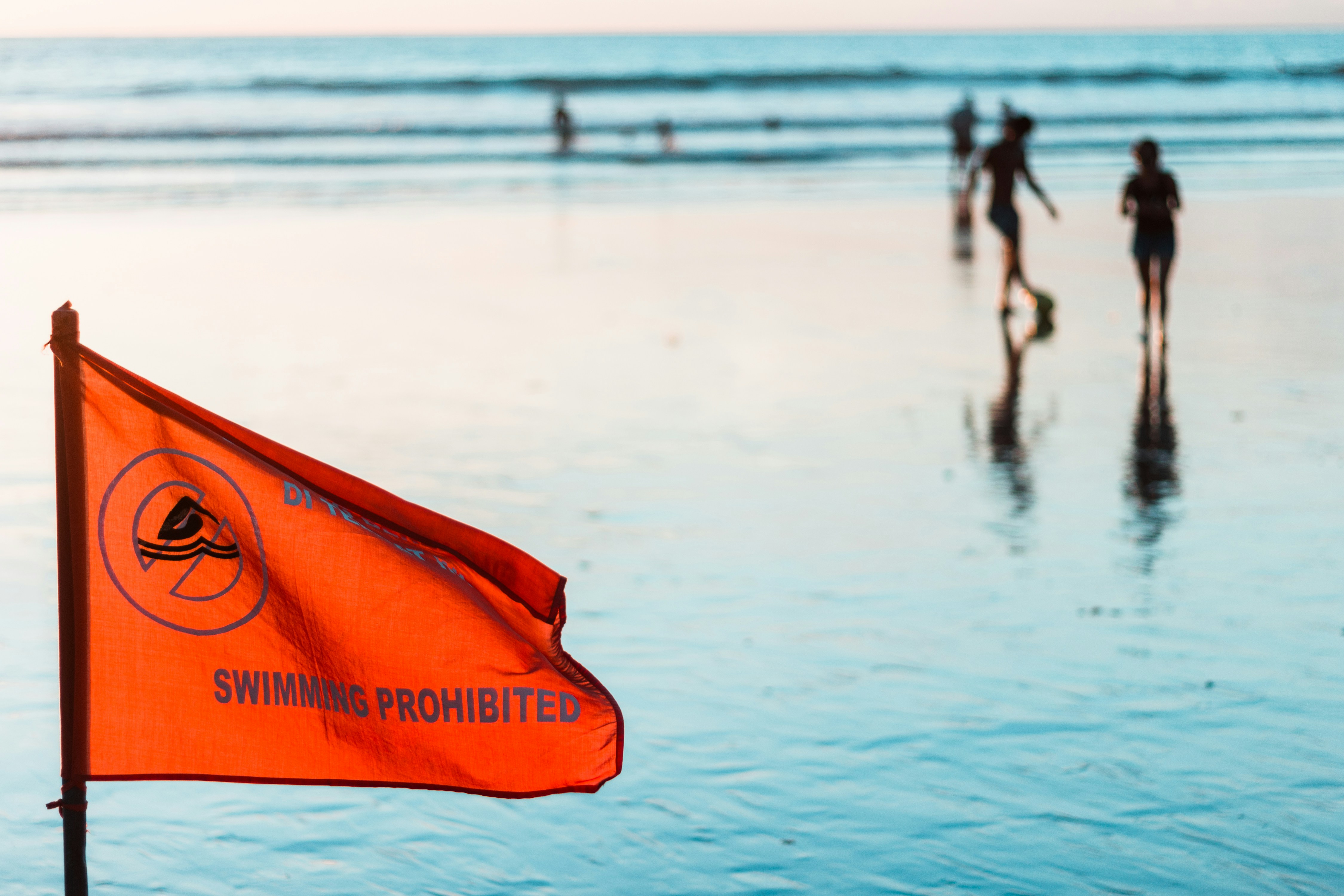 Red Prohibition Flag Anchors a Quiet Beach Scene